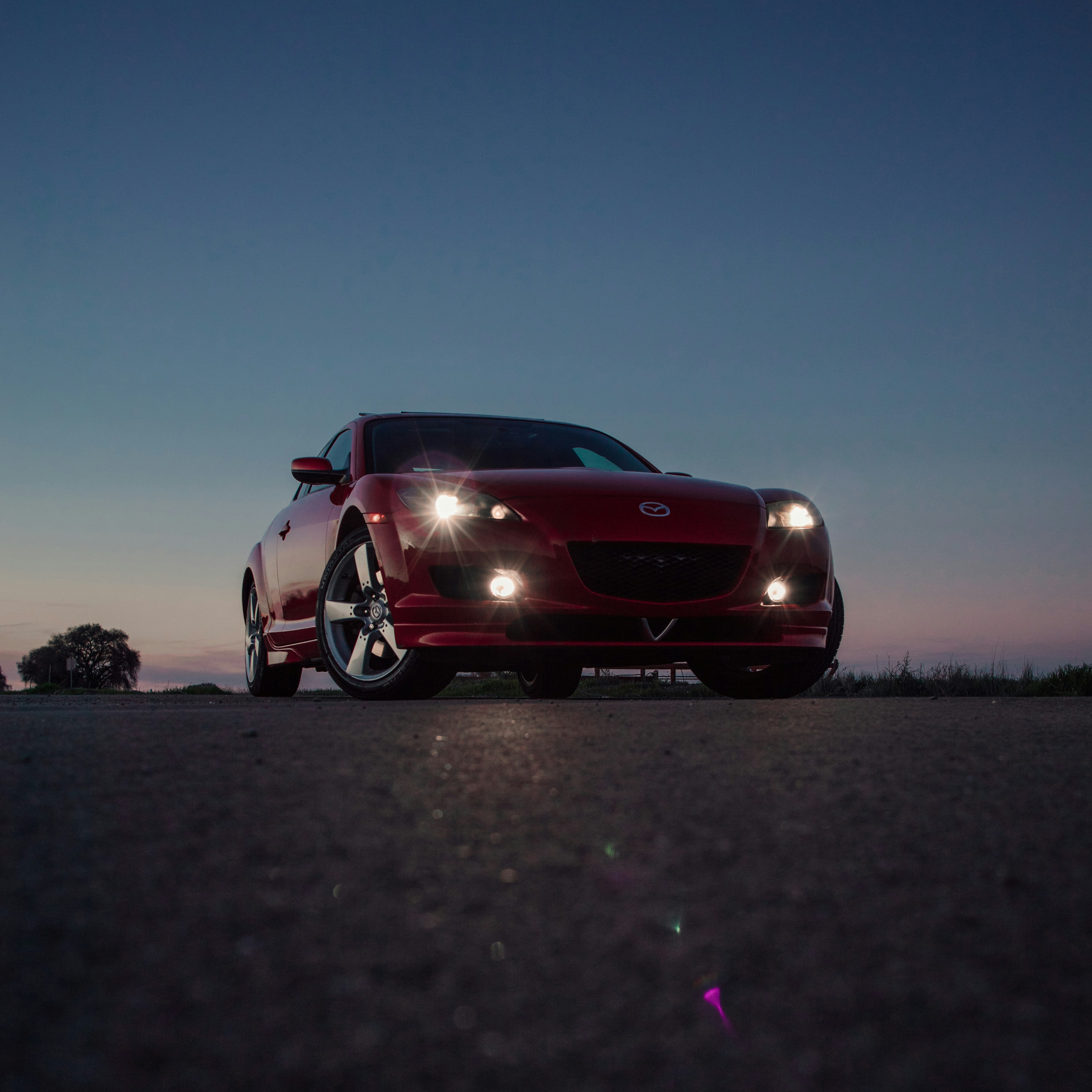 Dusk-Driven Red Coupe Under a Gradient Sky