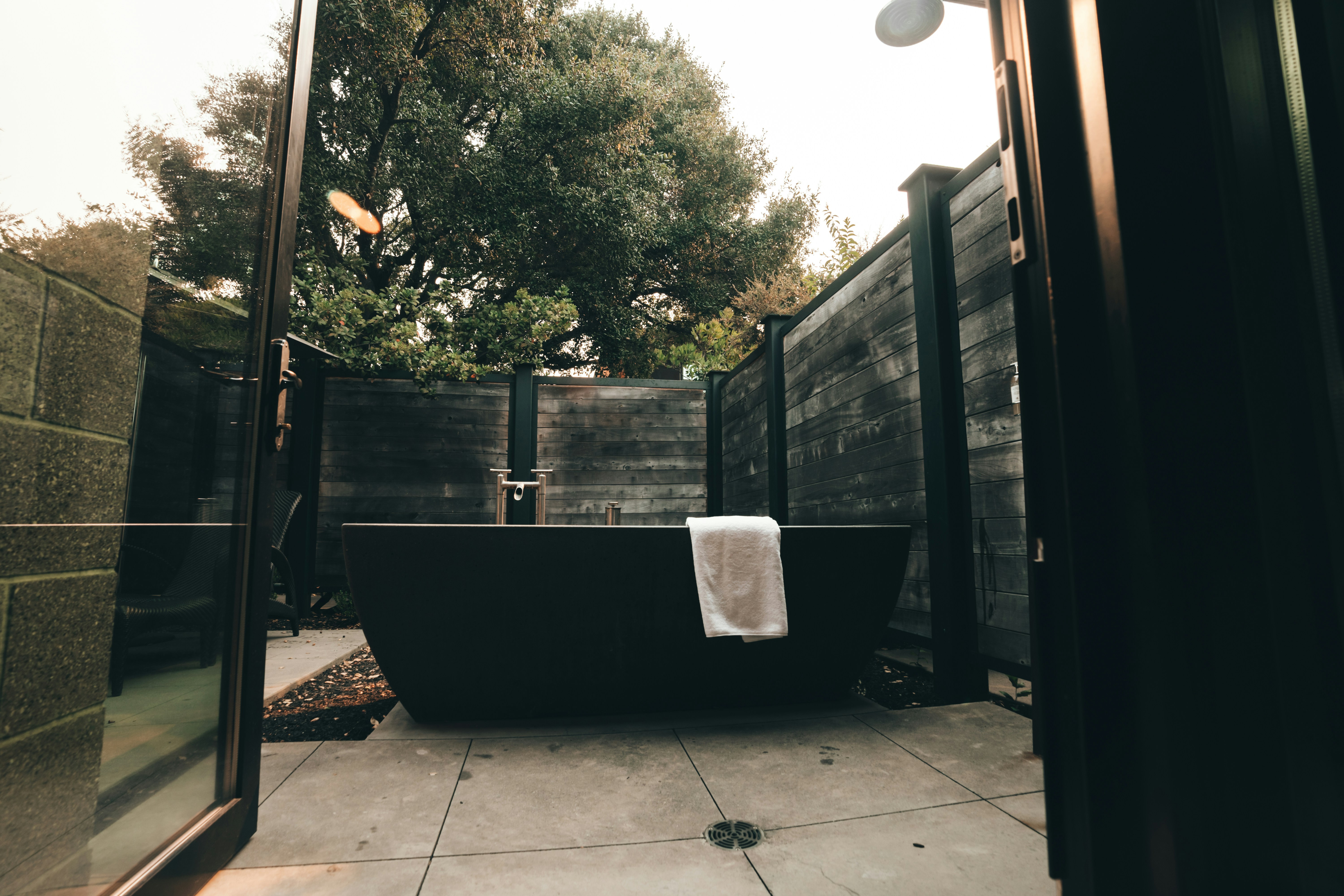a black bath tub sitting next to a wooden fence