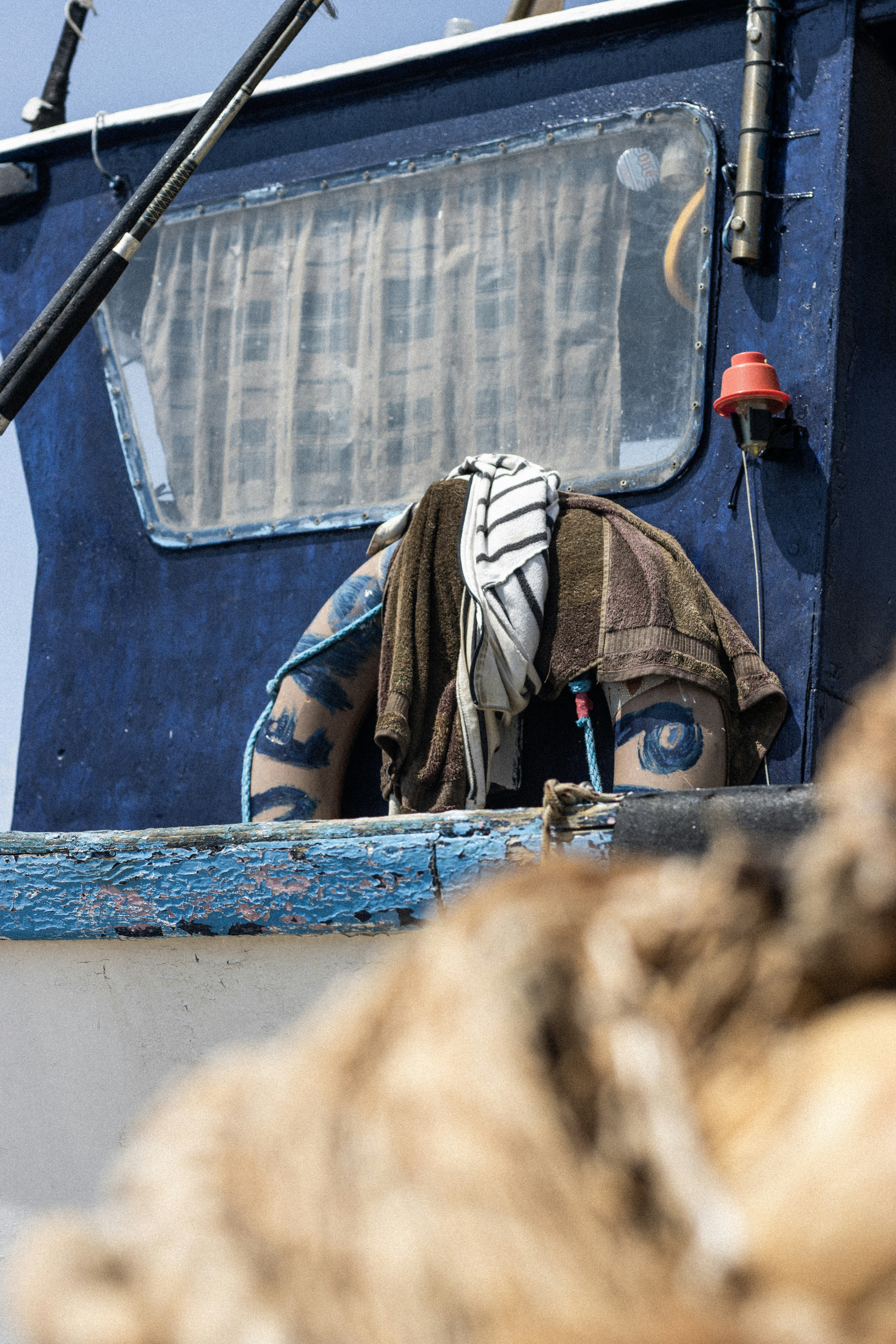 Hidden Crew at the Hull's Edge: Tattooed Arms and Striped Cloth in a Weathered Blue Boat