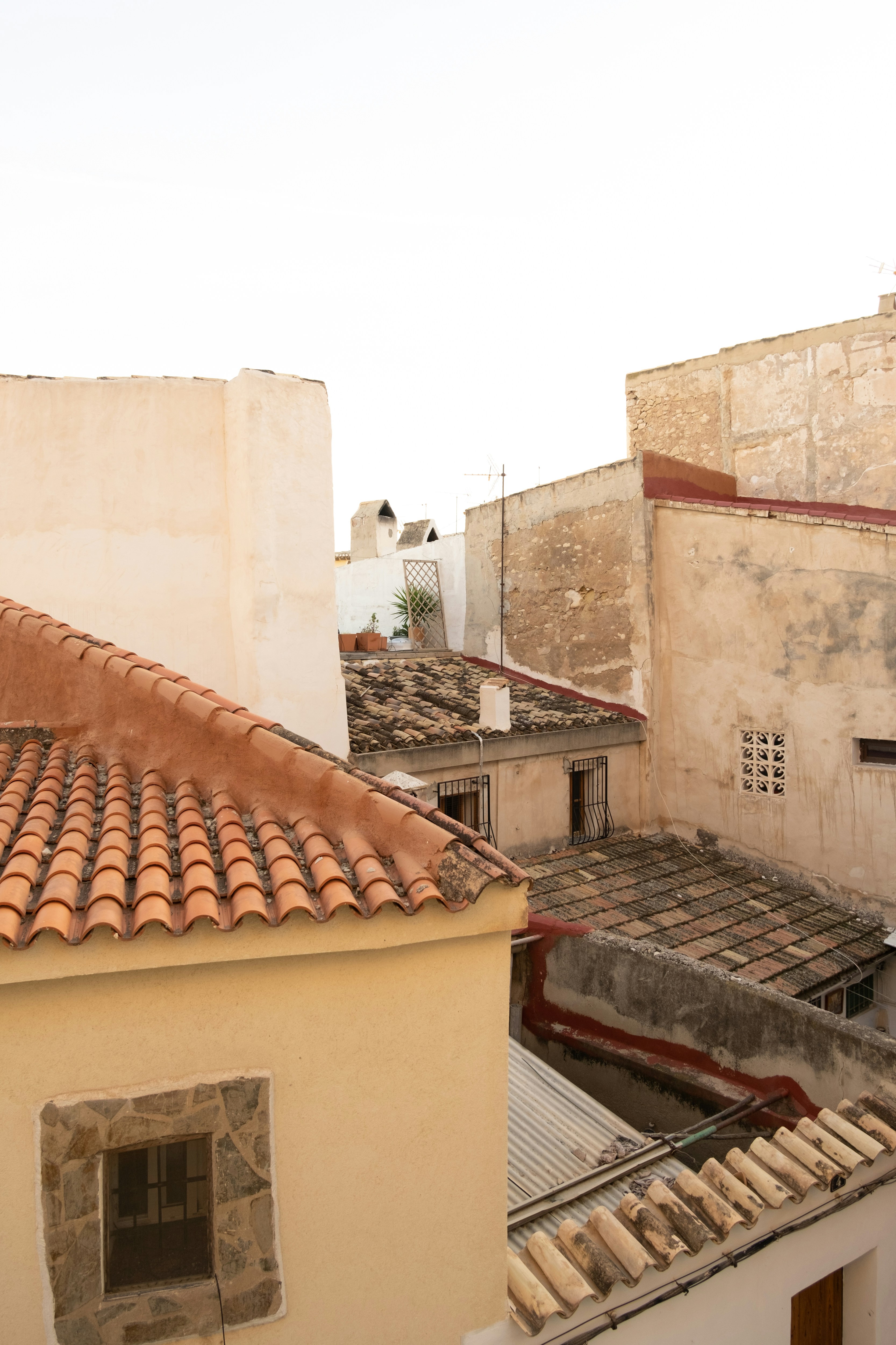 Brown ceramic rooftops of an old village in Spain. | a view of rooftops and buildings in a city