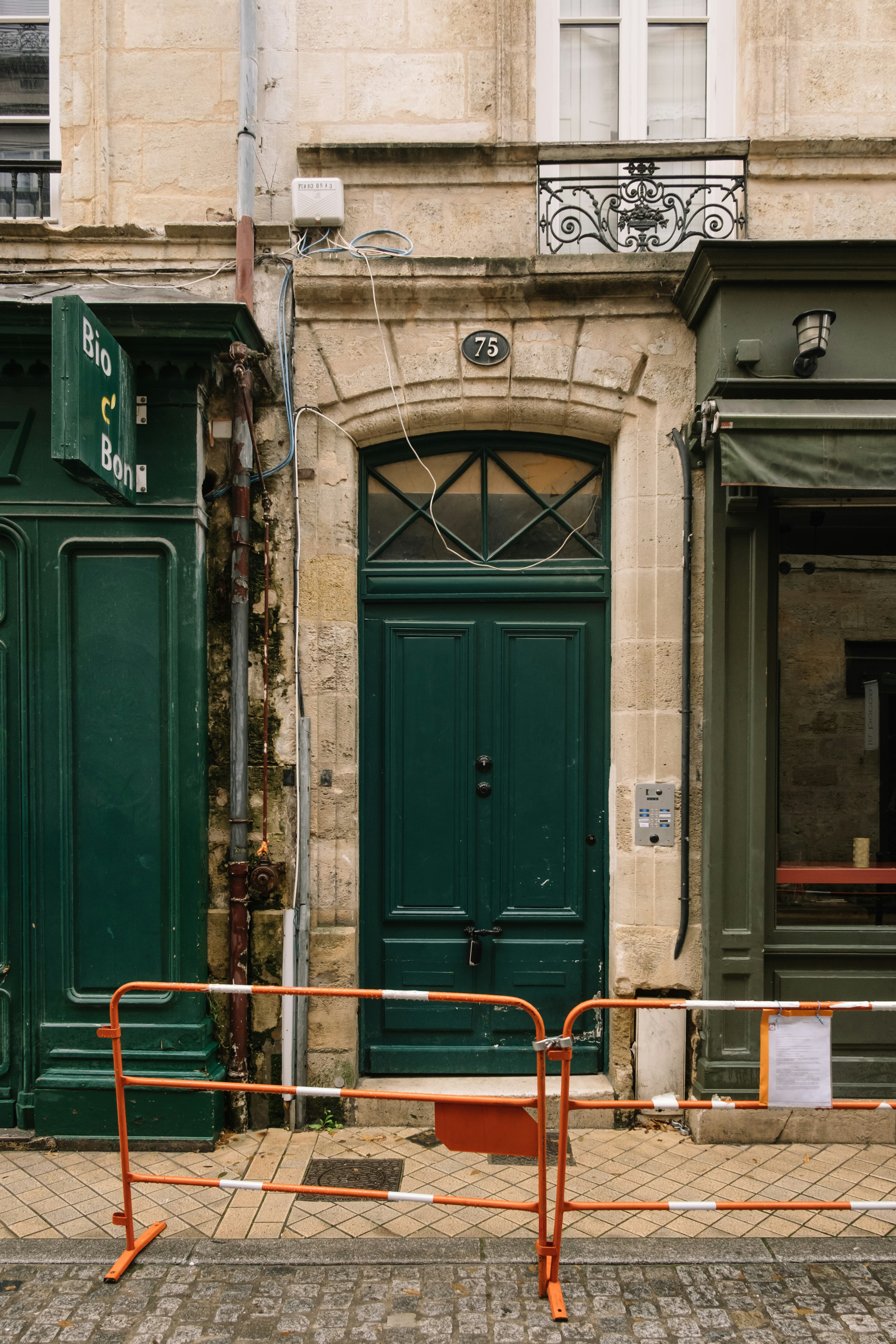 A street view of Bordeaux, France. A green ornate door entrance. Building straight view.