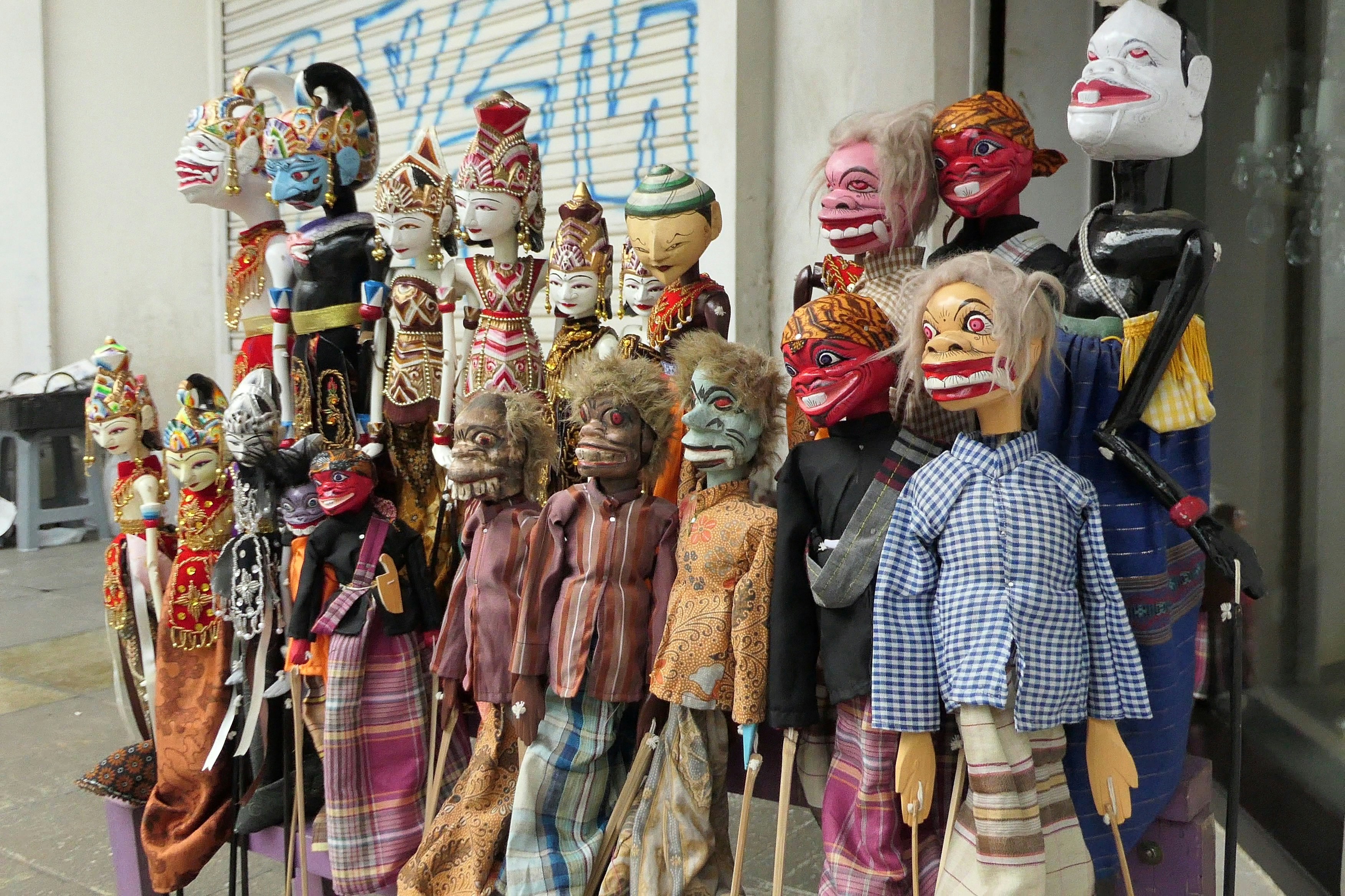 A vibrant display of traditional puppets, showcasing intricate designs and expressive features, arranged in a lively outdoor setting.