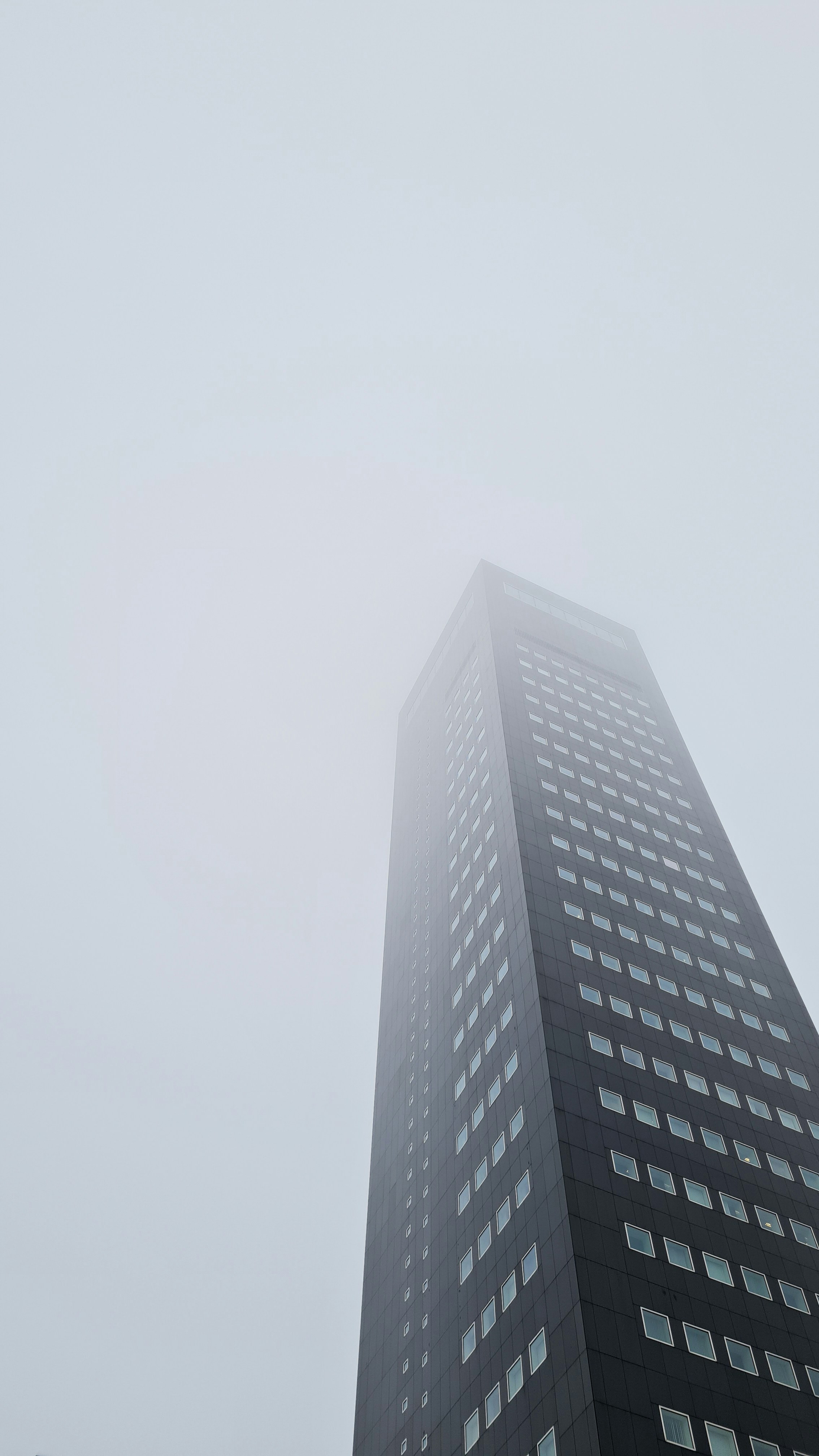 A tall building with lots of windows on a foggy day photo – Free ...