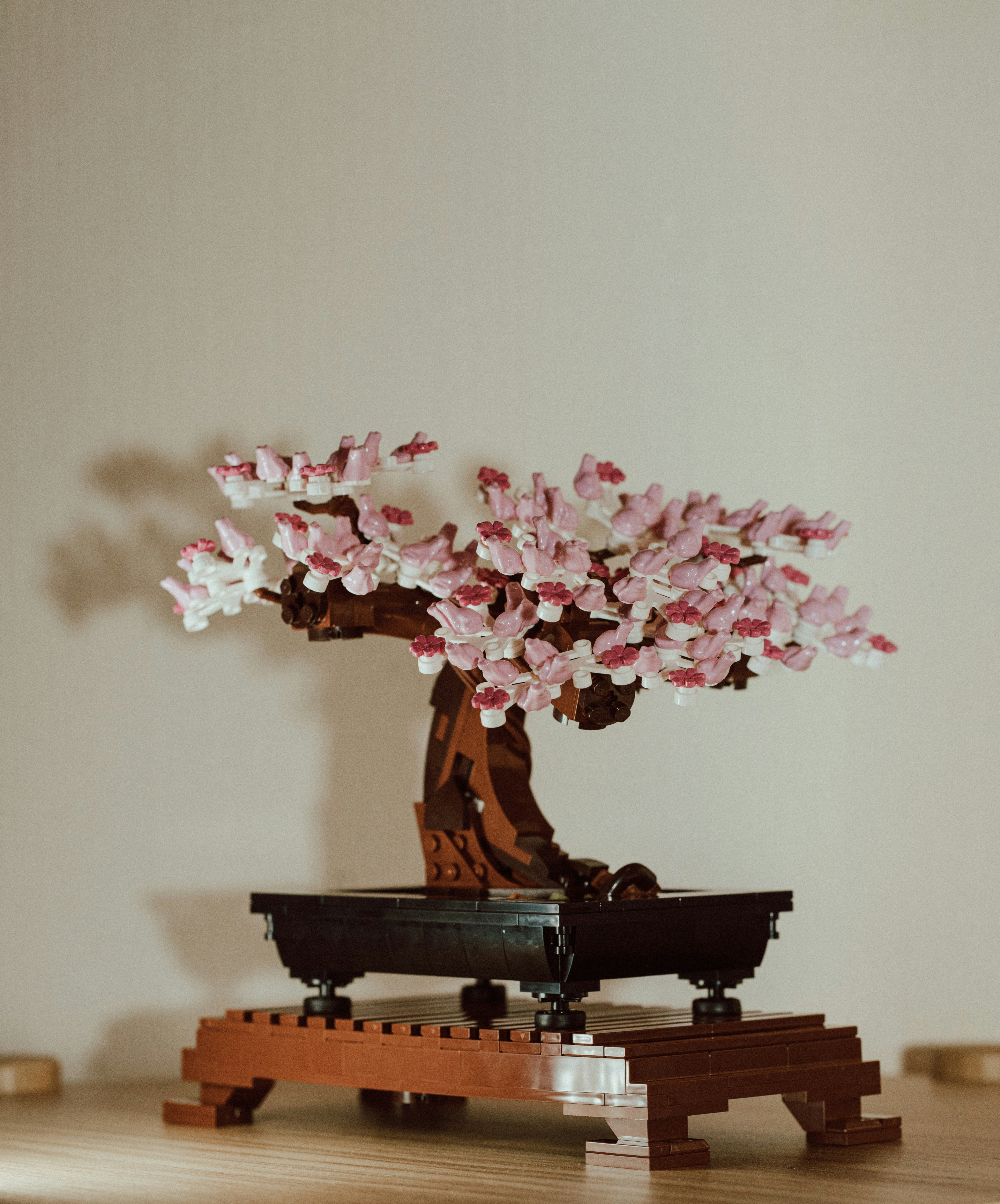 a bonsai tree with pink flowers on a wooden table