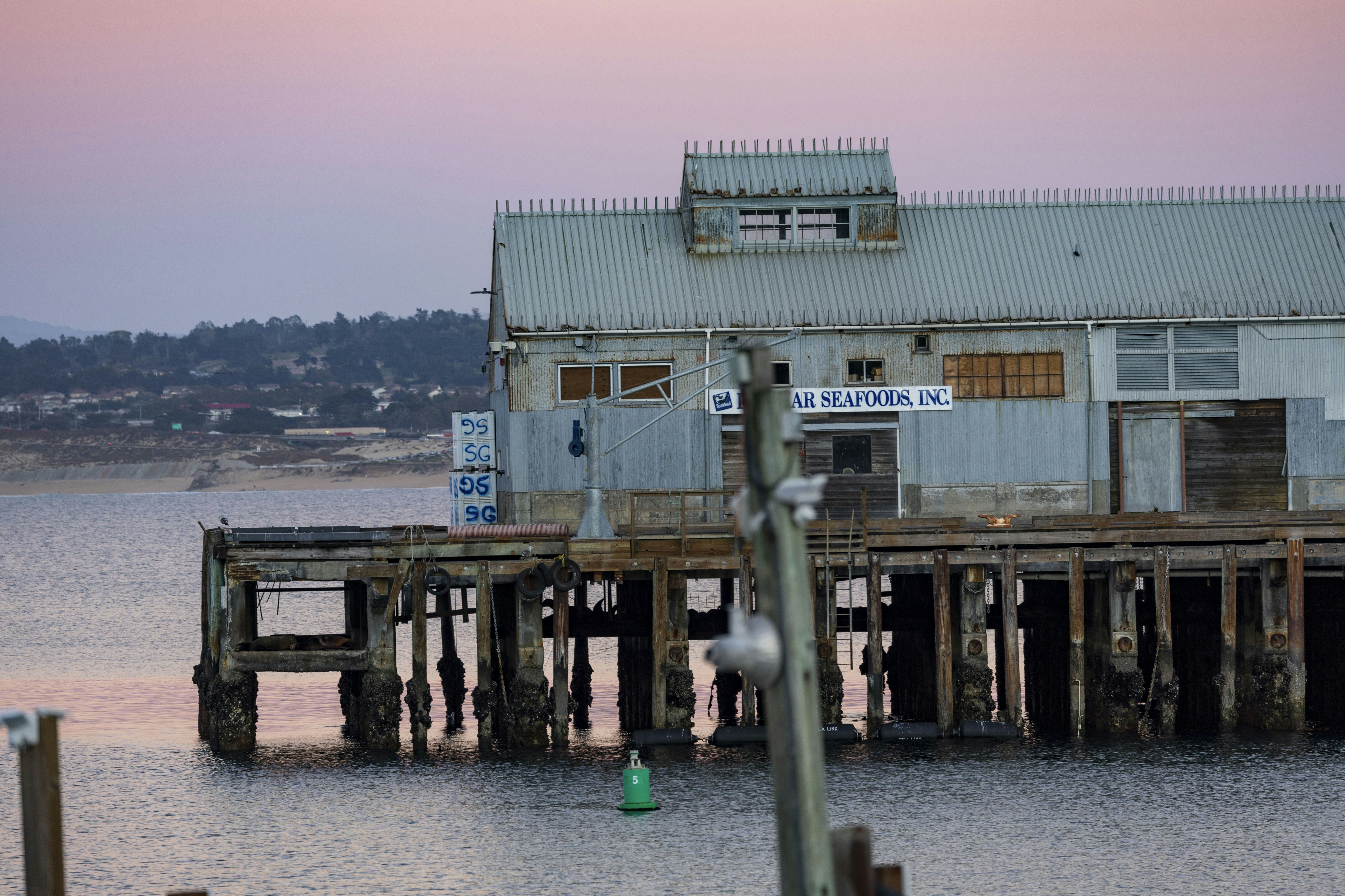 A building sitting on top of a pier next to a body of water photo ...