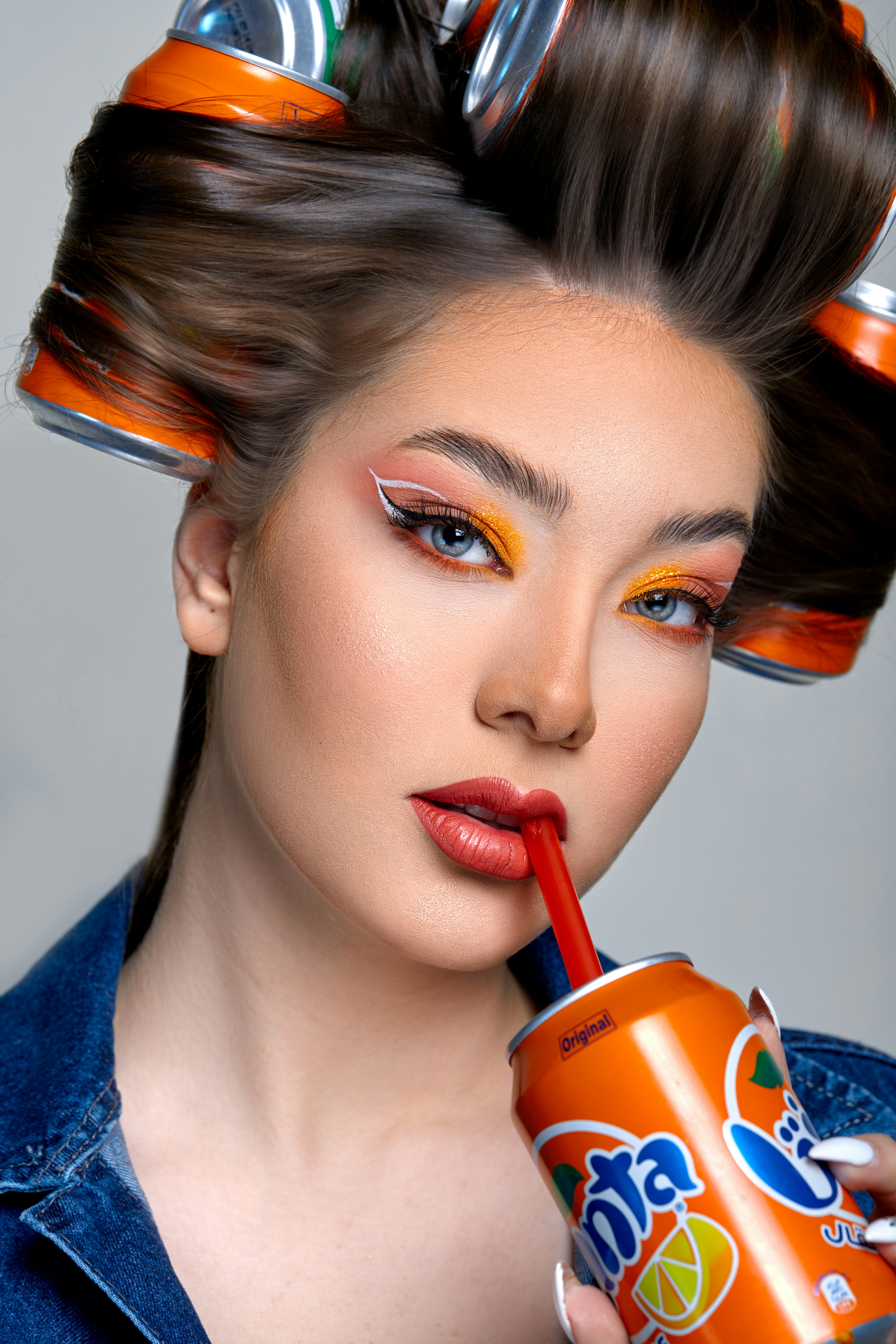 A woman with orange lipstick and curlers on her head drinking a drink ...