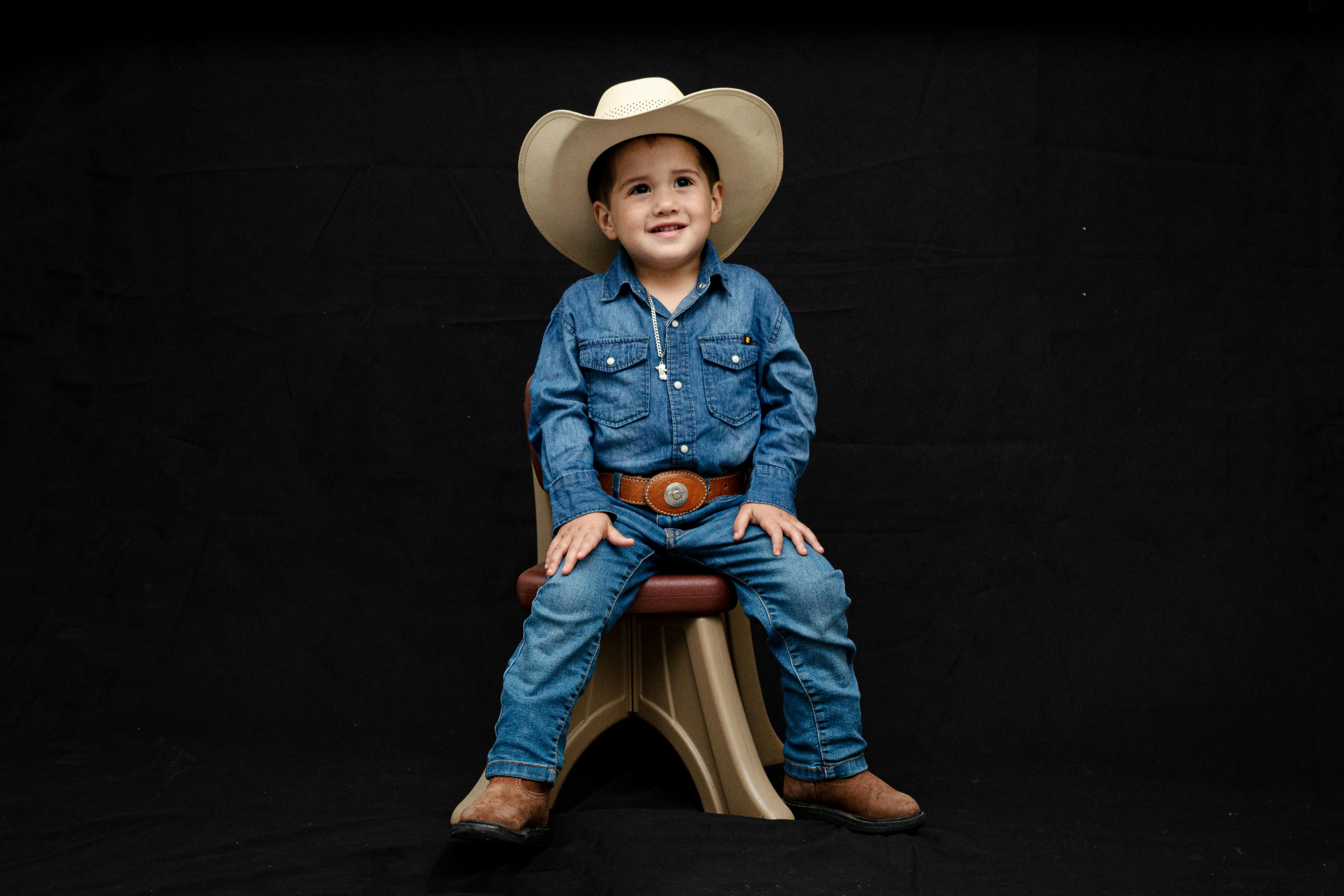 A young boy wearing a cowboy hat sitting on a stool photo – Free ...