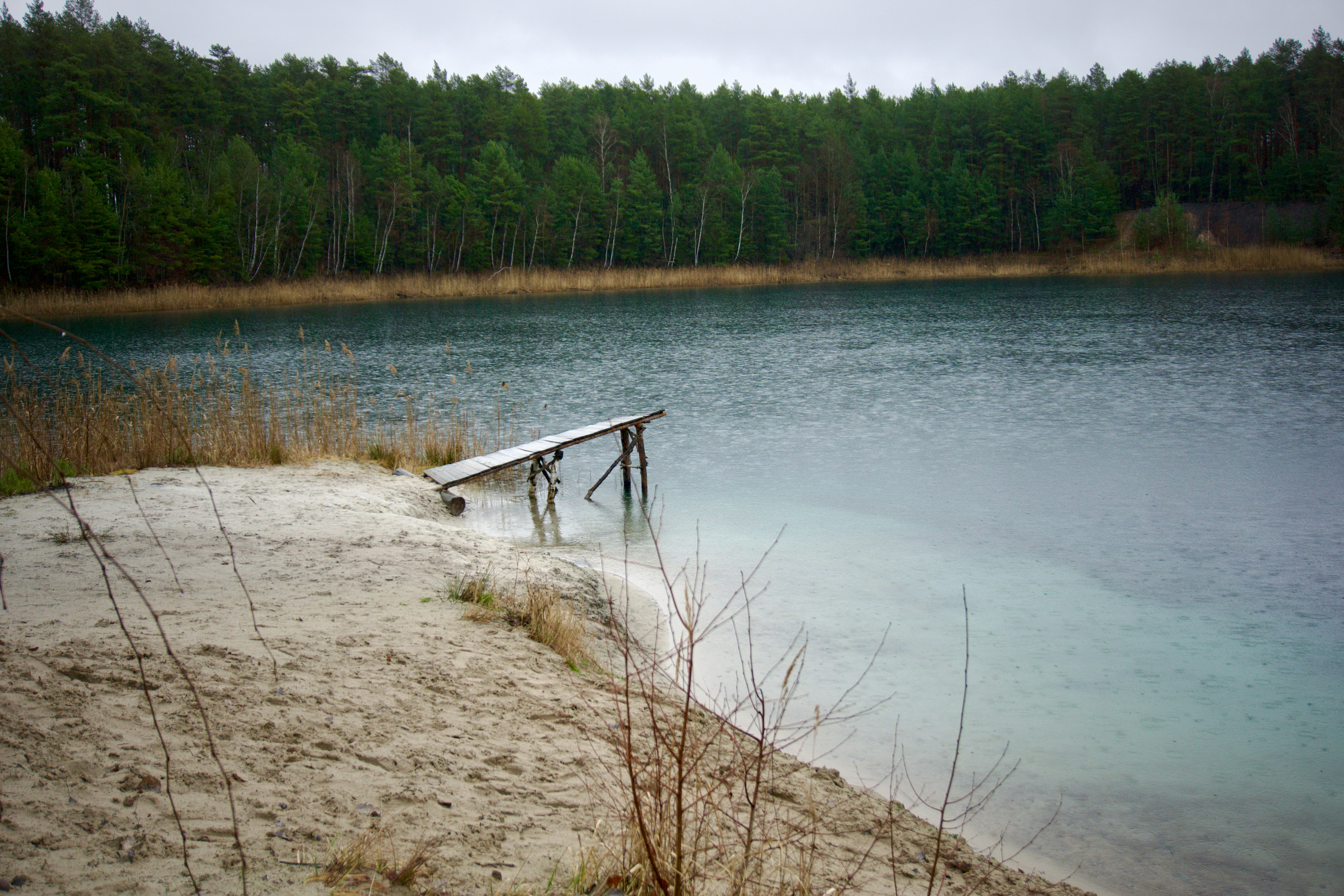 A turquoise blue lake under light rain
