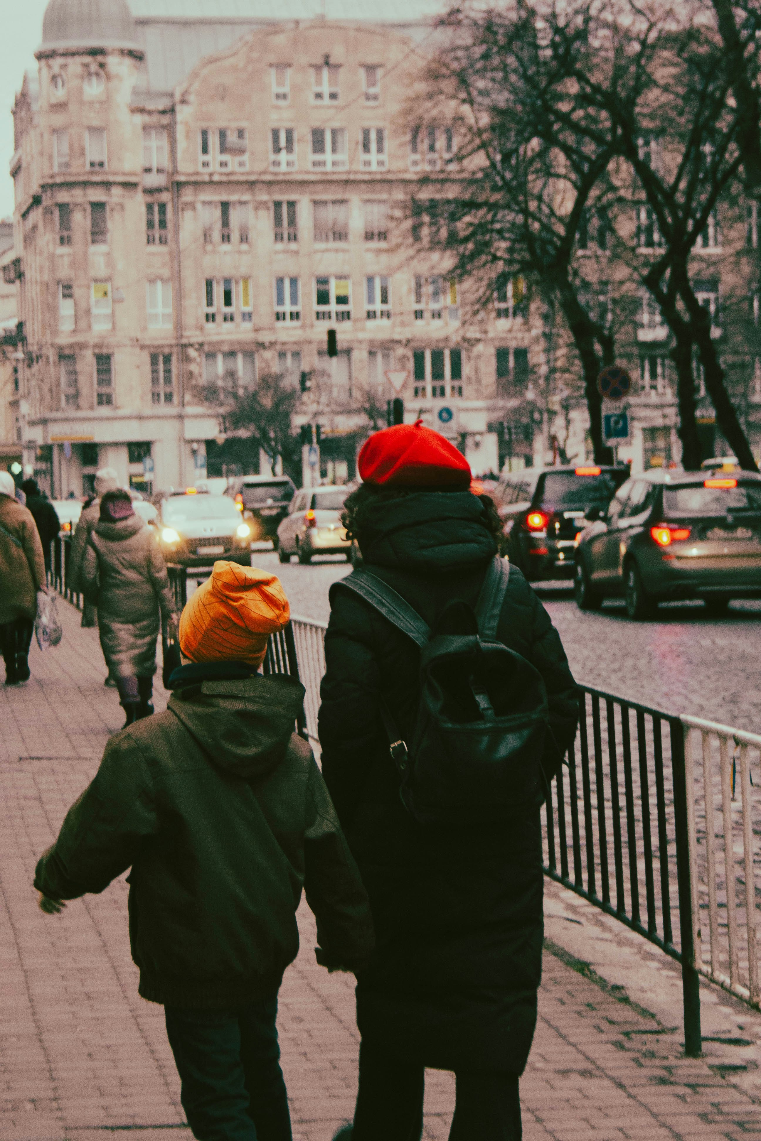 Two figures in winter street glow: a red beret leads the way