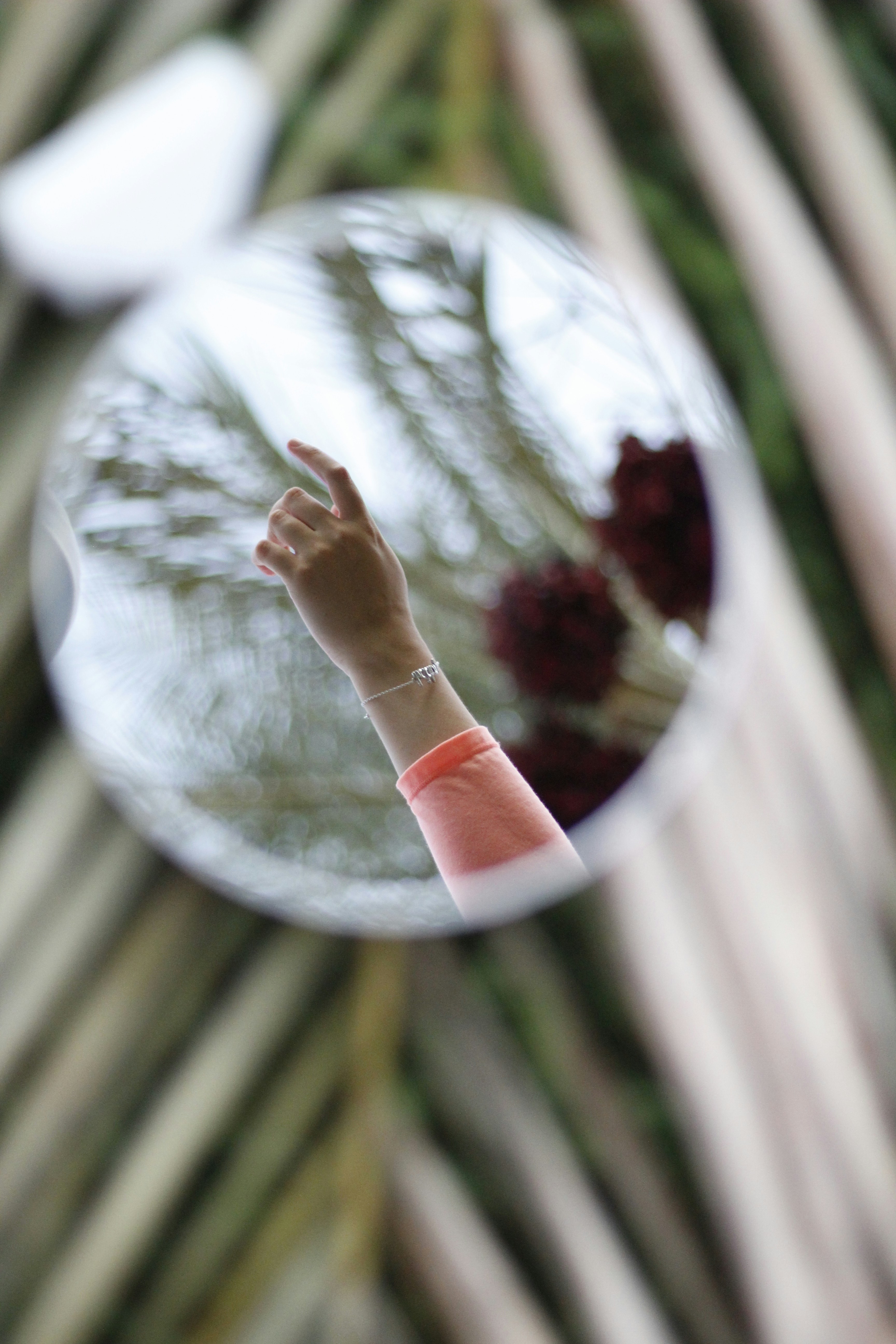 Within the Orb: A Delicate Hand Reaches Through a Circular Mirror