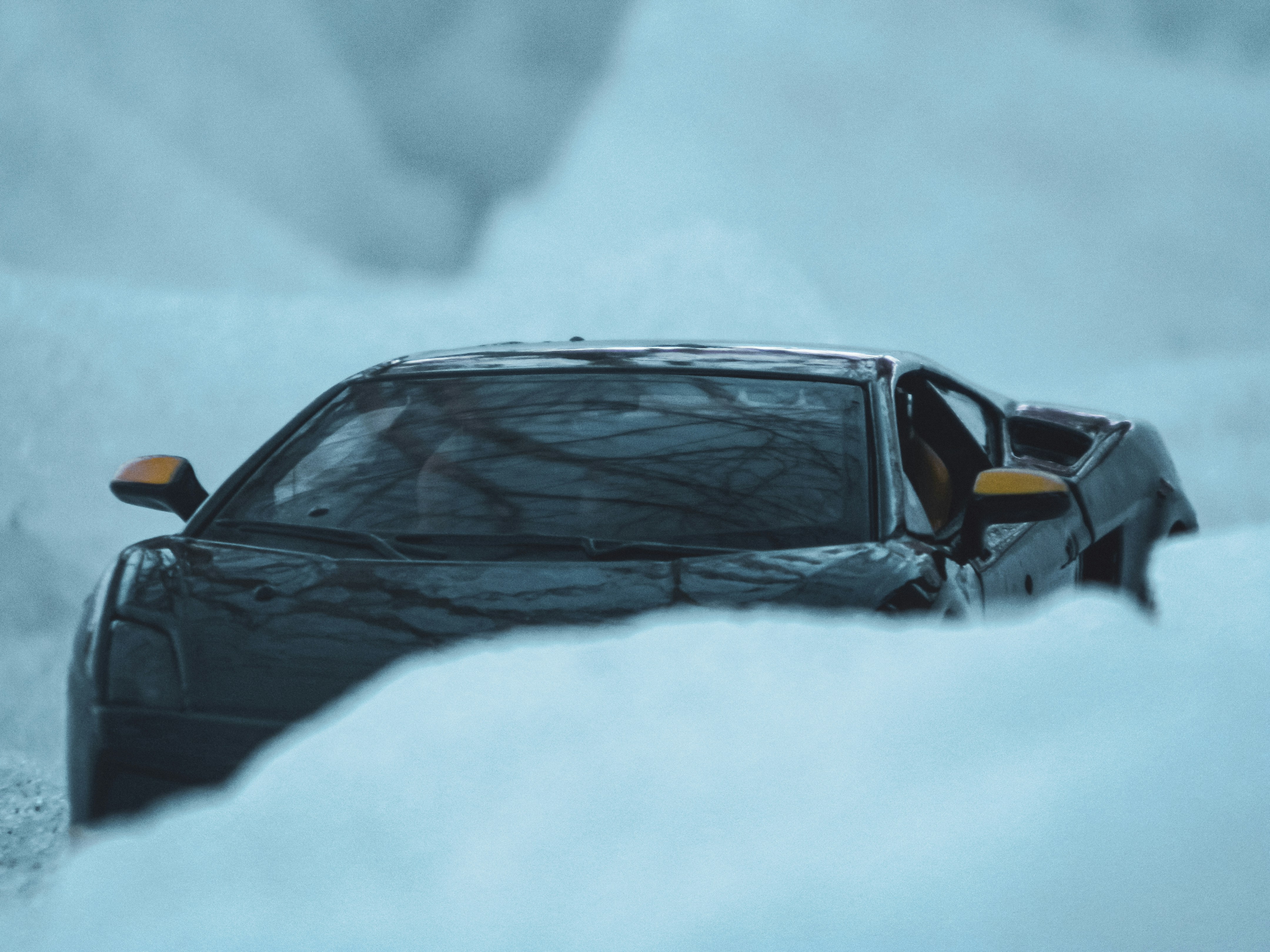 Black sports car partially submerged in snow with blurred icy background.