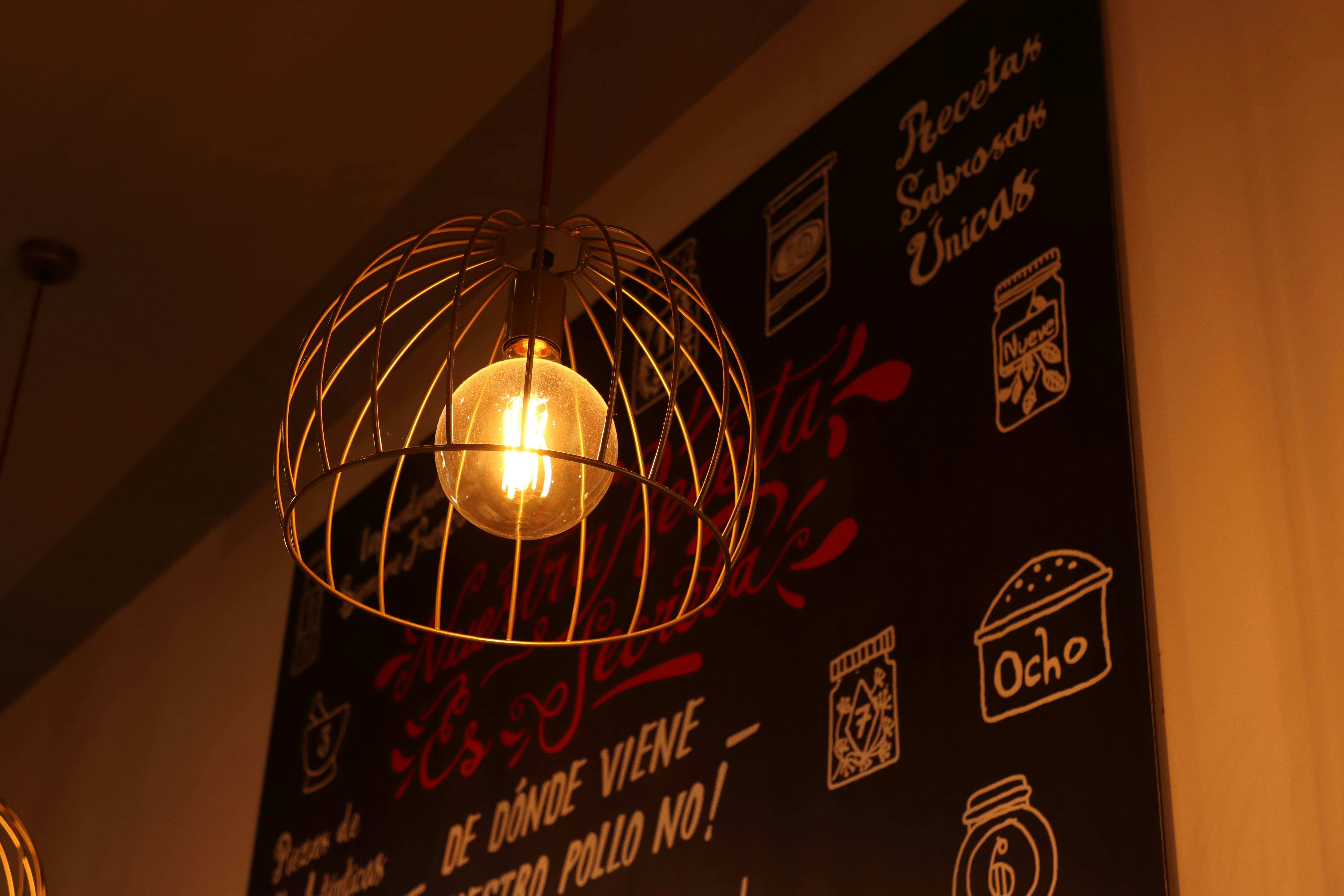 Warm Glow Through a Cage: A Night Photo of Hanging Light Against Chalkboard Decor