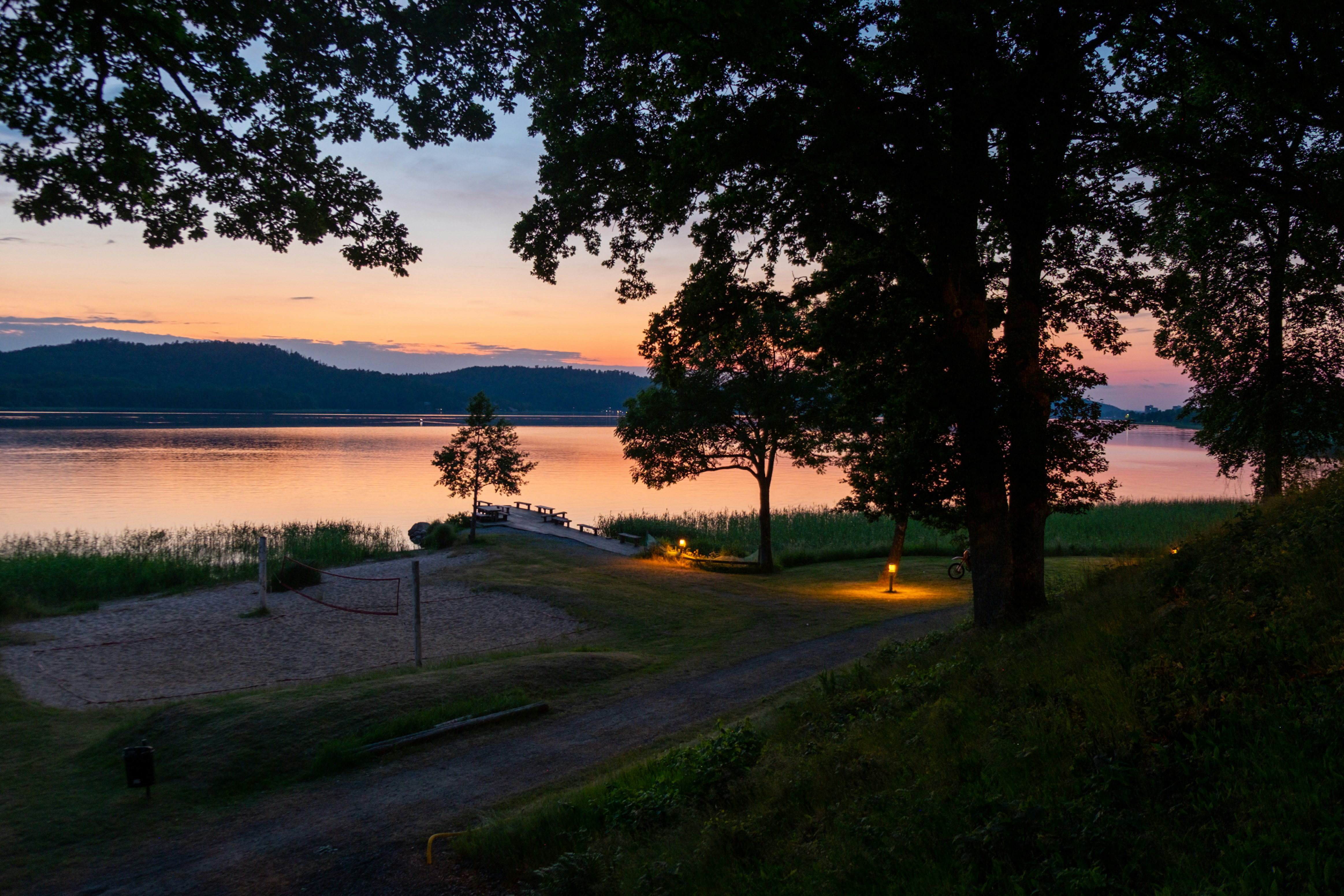 A sunset view of a lake with a boat on the shore photo – Free Sunset ...