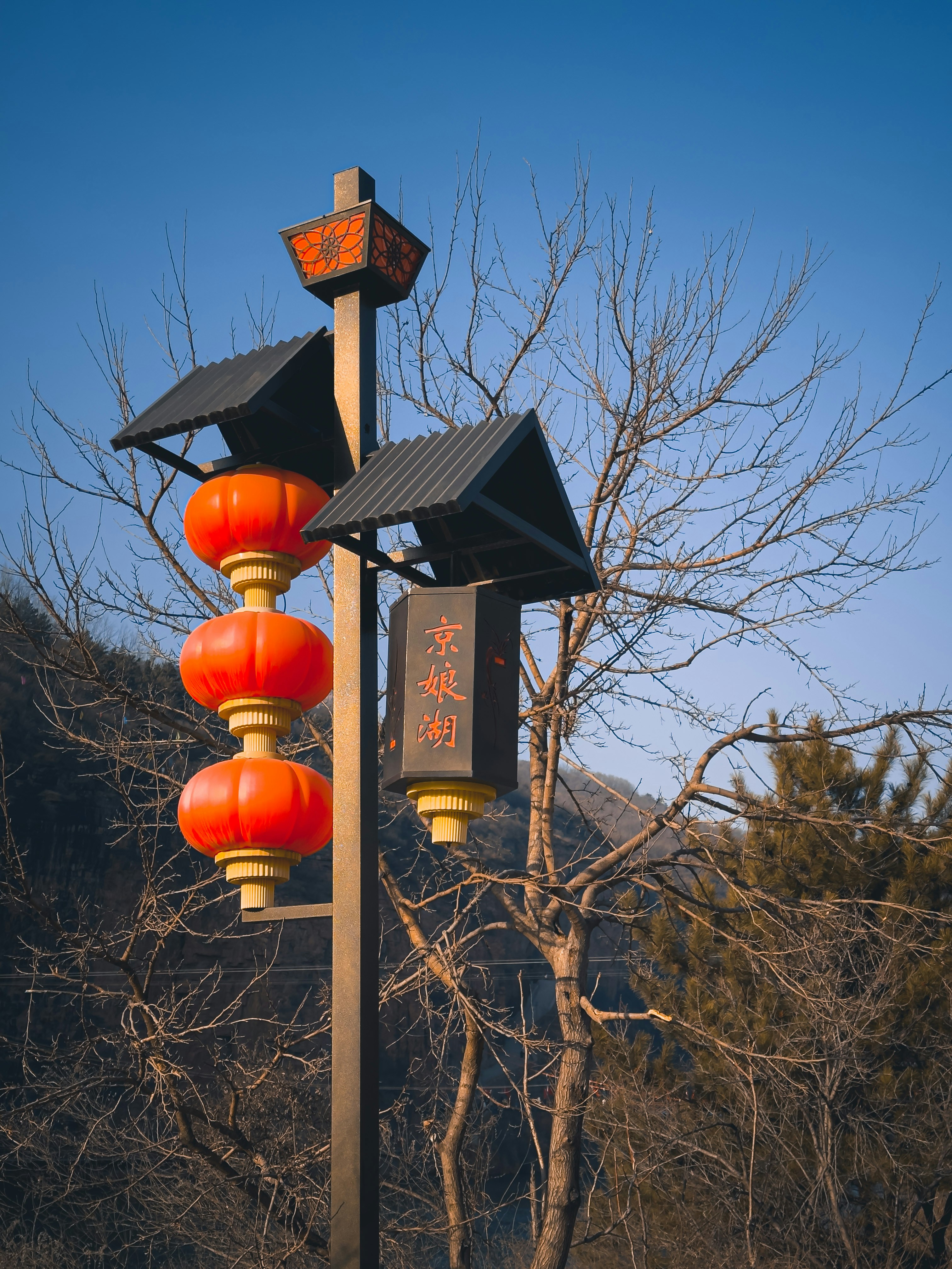 Three Scarlet Orbs on a Lantern Post Against a Crisp Winter Sky