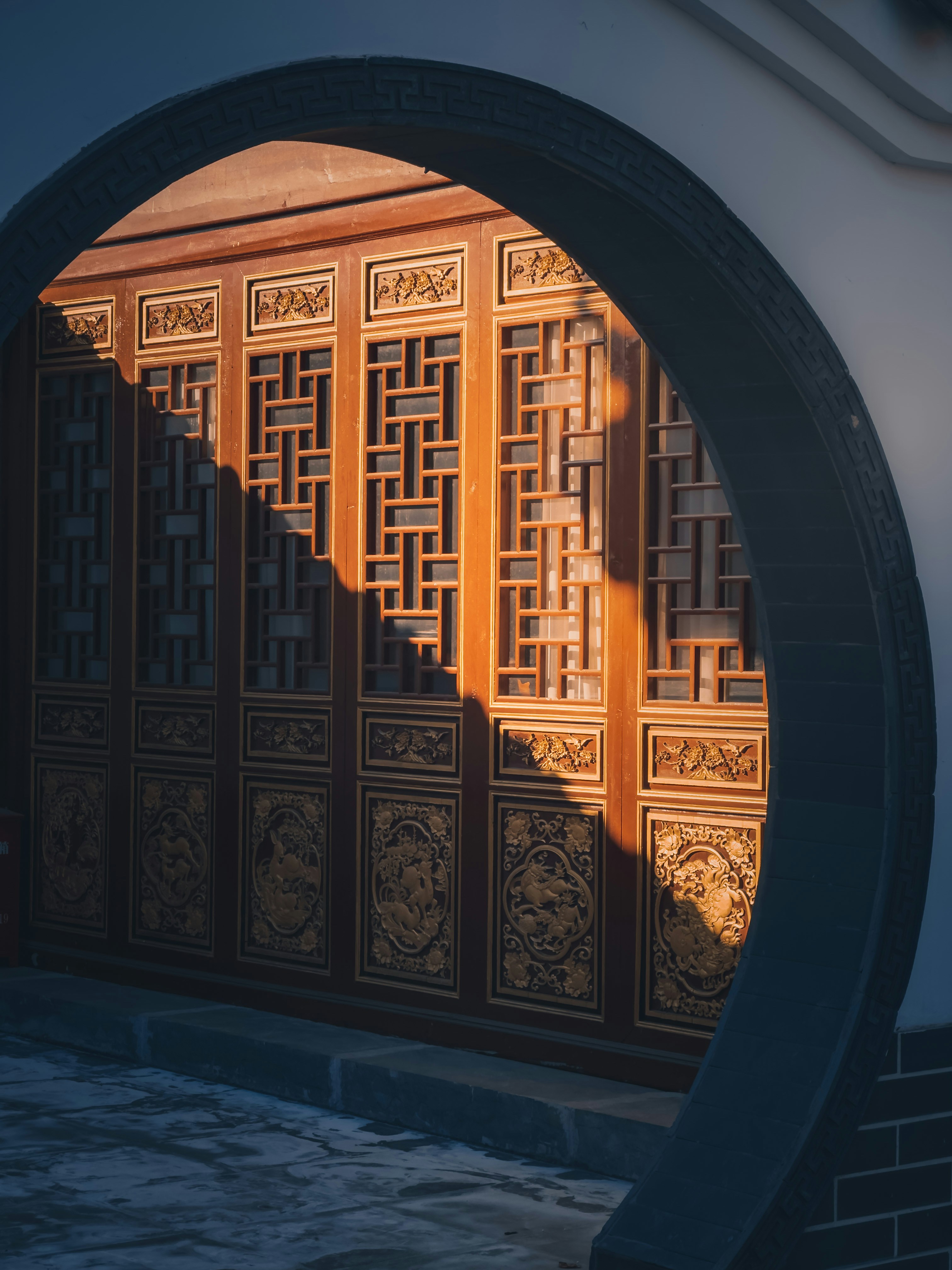 Moon Gate in Warm Light: Intricate Woodwork Framed by a Circular Arch