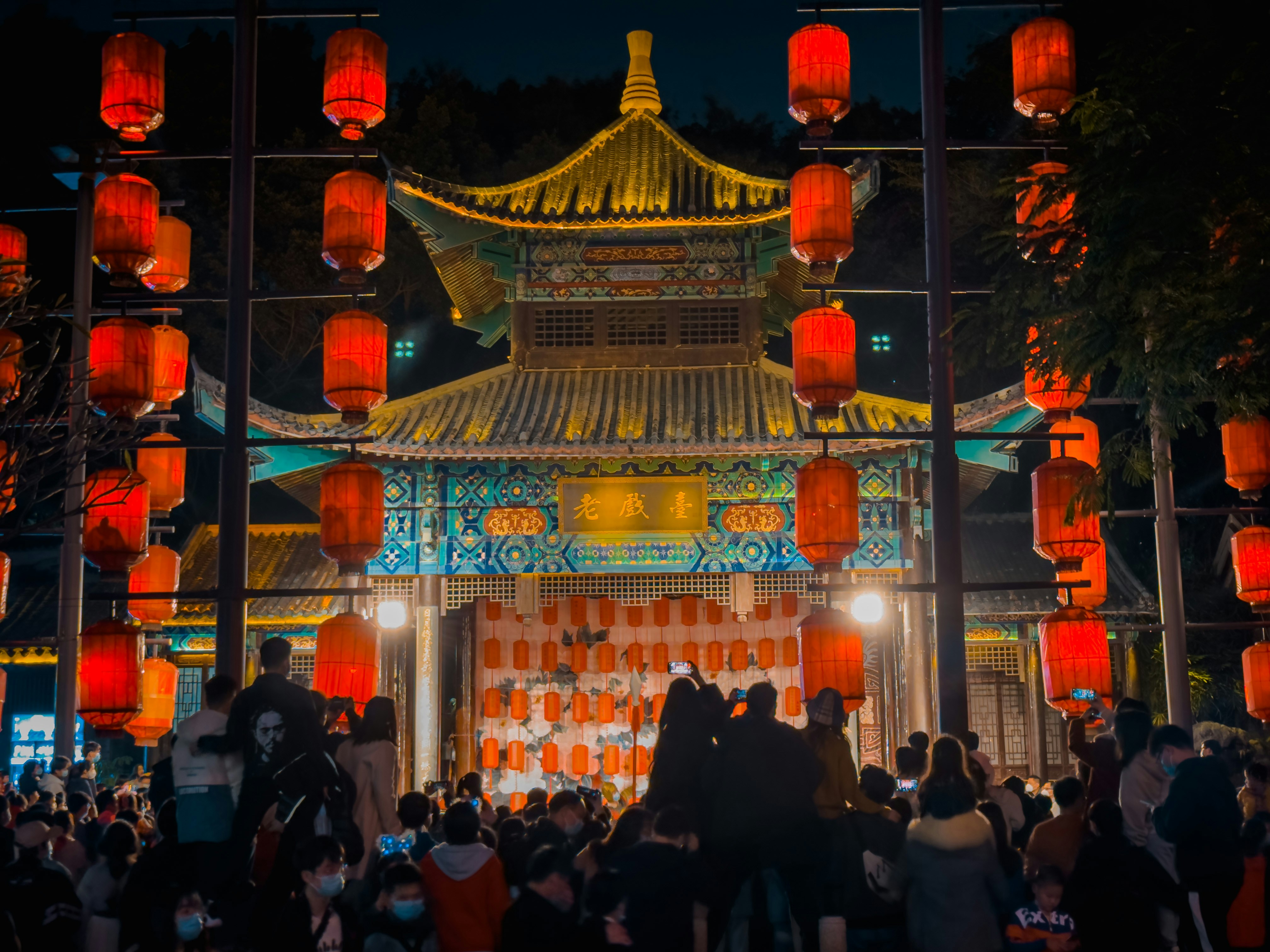 Lantern-lit Temple Gate at Night: Crowds Framing an Ornate Entrance