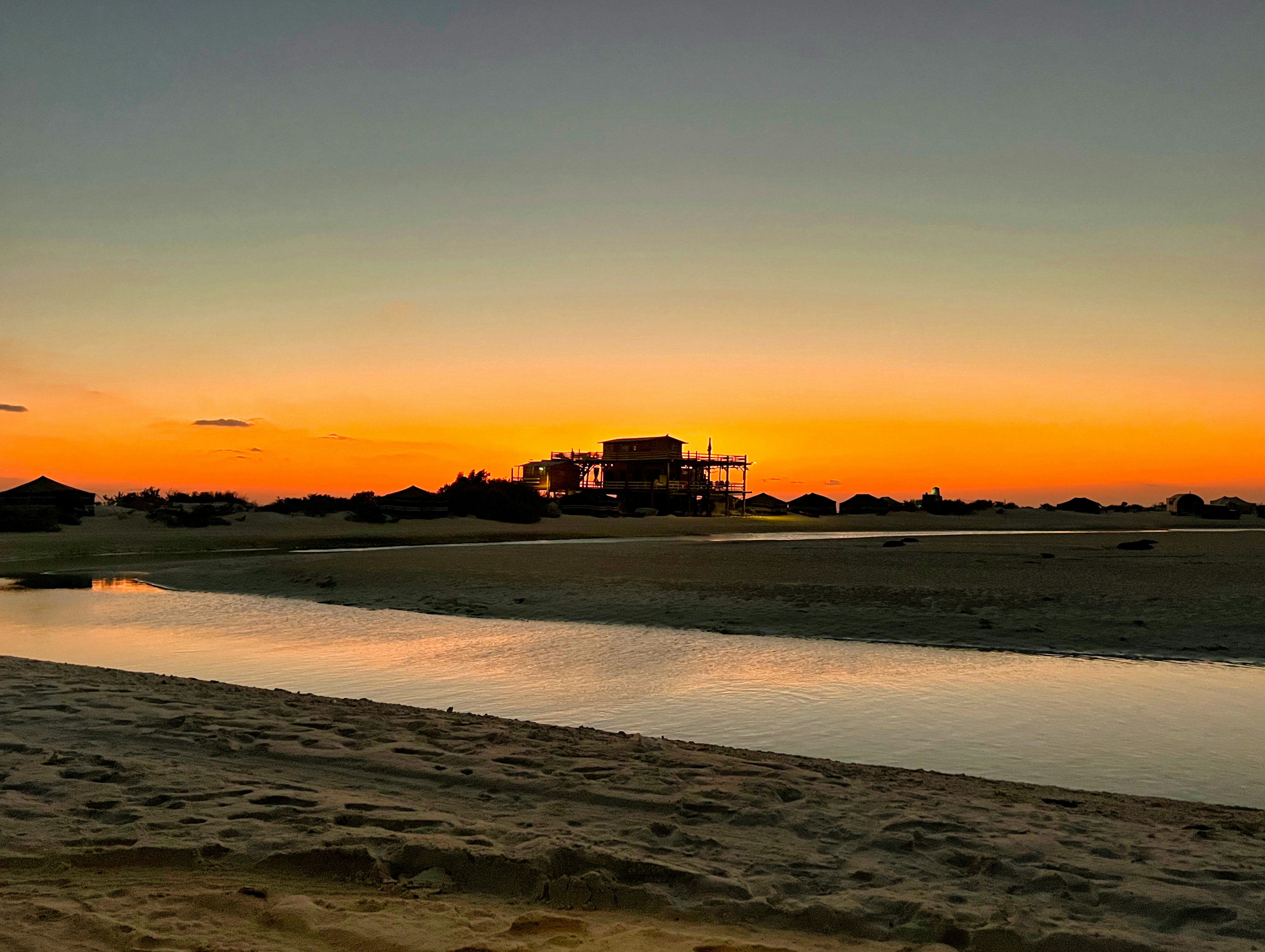 Horizon Silhouette: A Coastal Structure Framed by a Sunset Channel