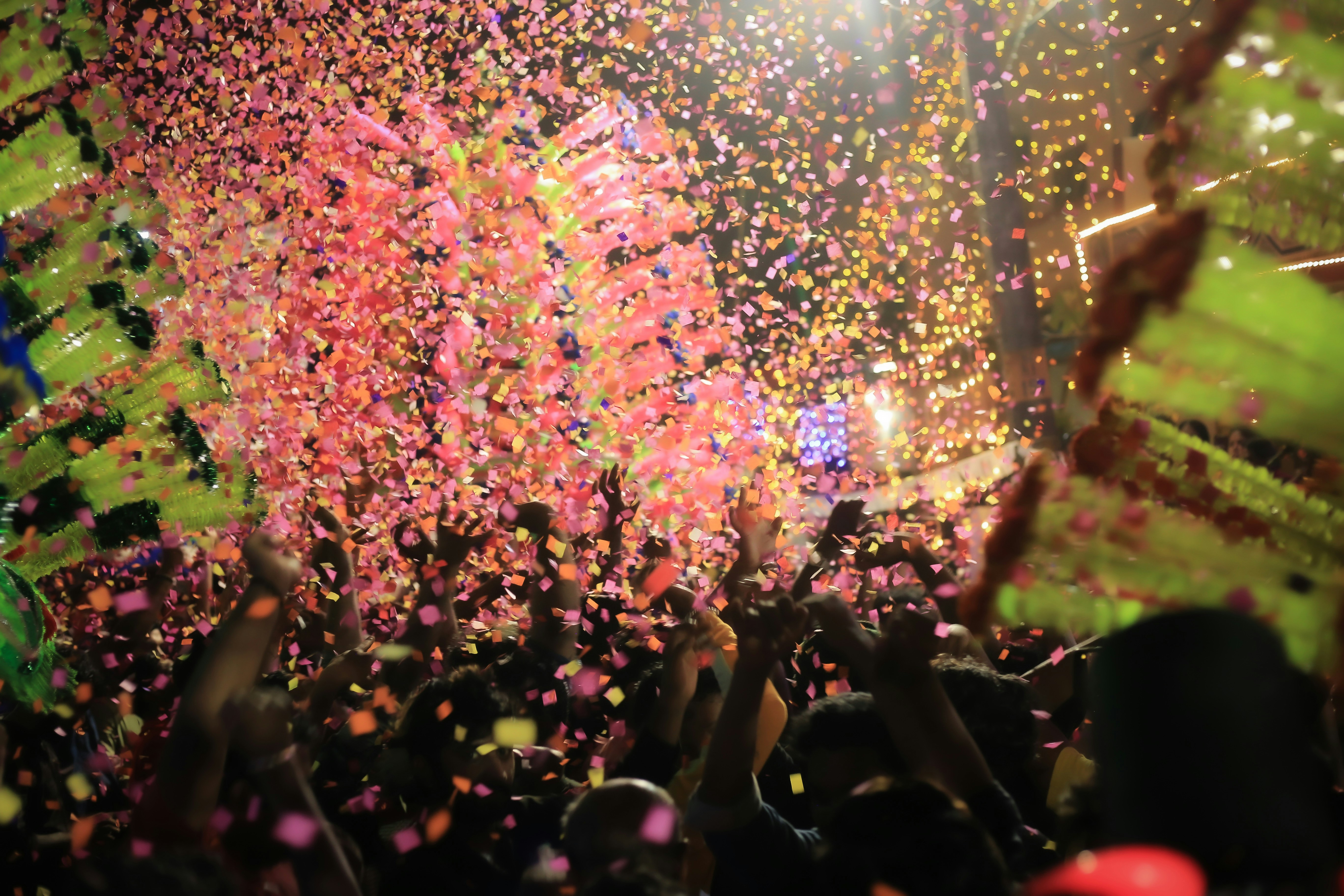 A crowd of people are throwing confetti in the air photo – Free Kerala ...