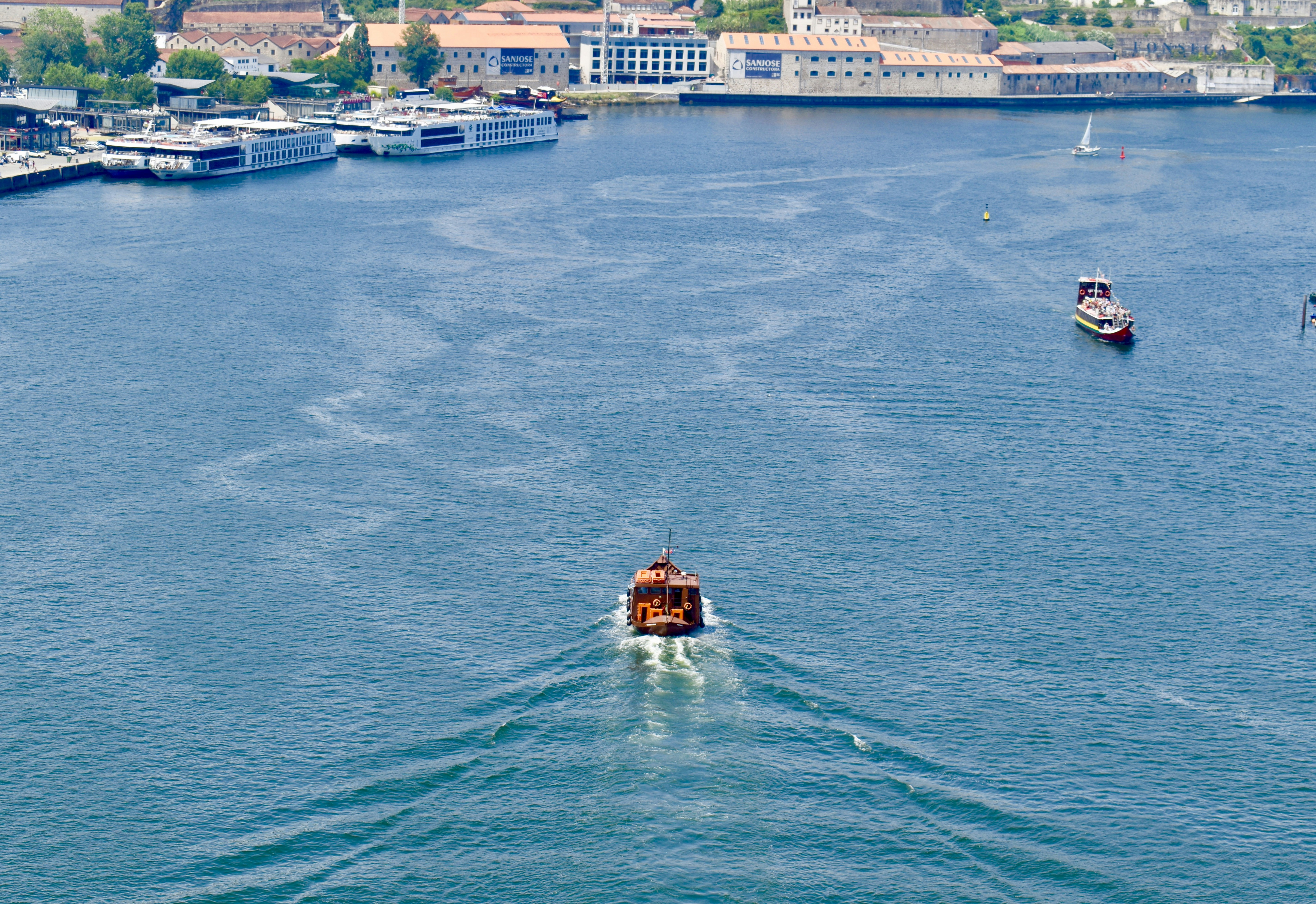 Orange motorboat carving a white wake across a sunlit harbor