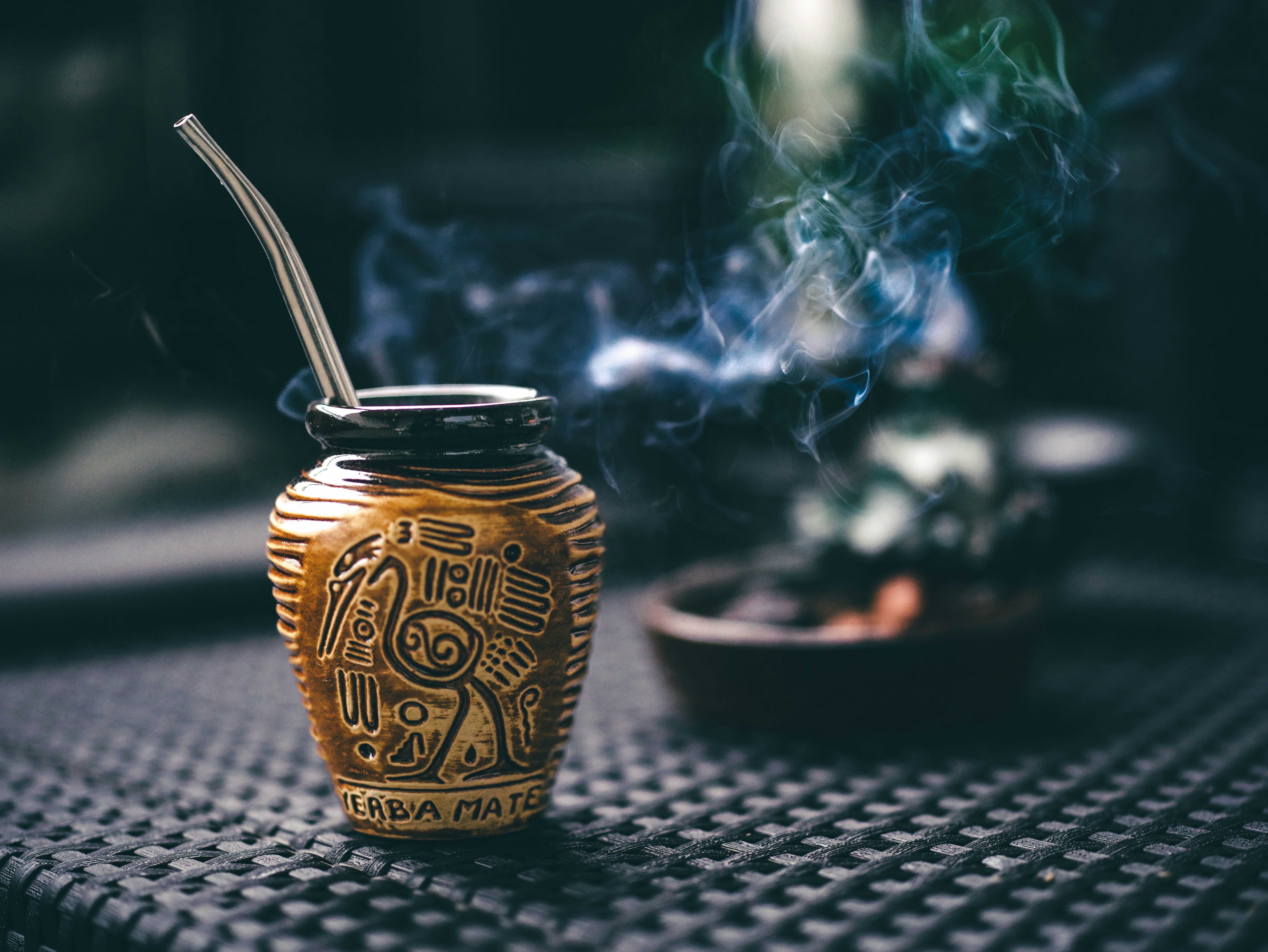 Glyph-Lined Mate Gourd Beside Rising Steam on a Woven Surface