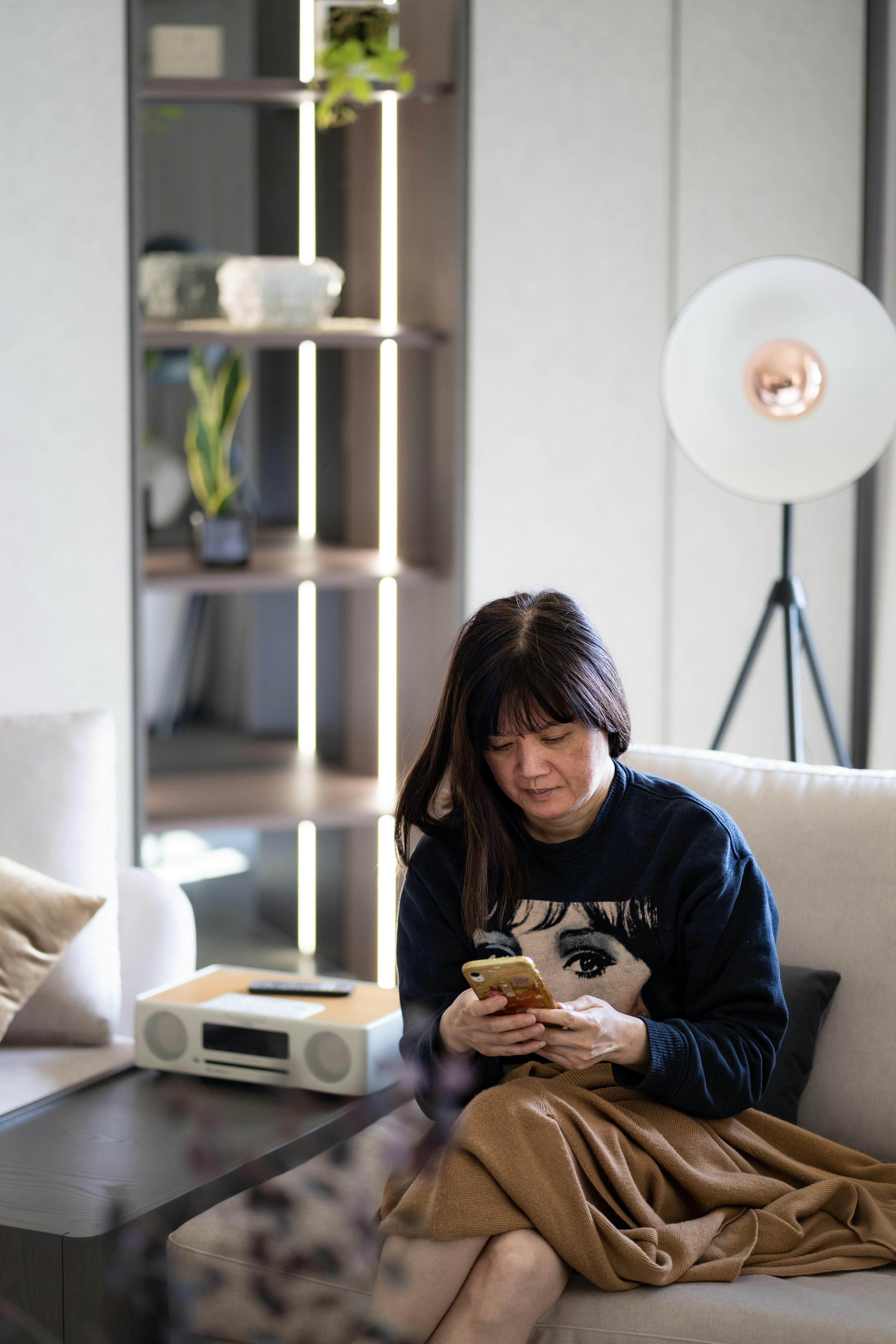 a woman sitting on a couch looking at a cell phone