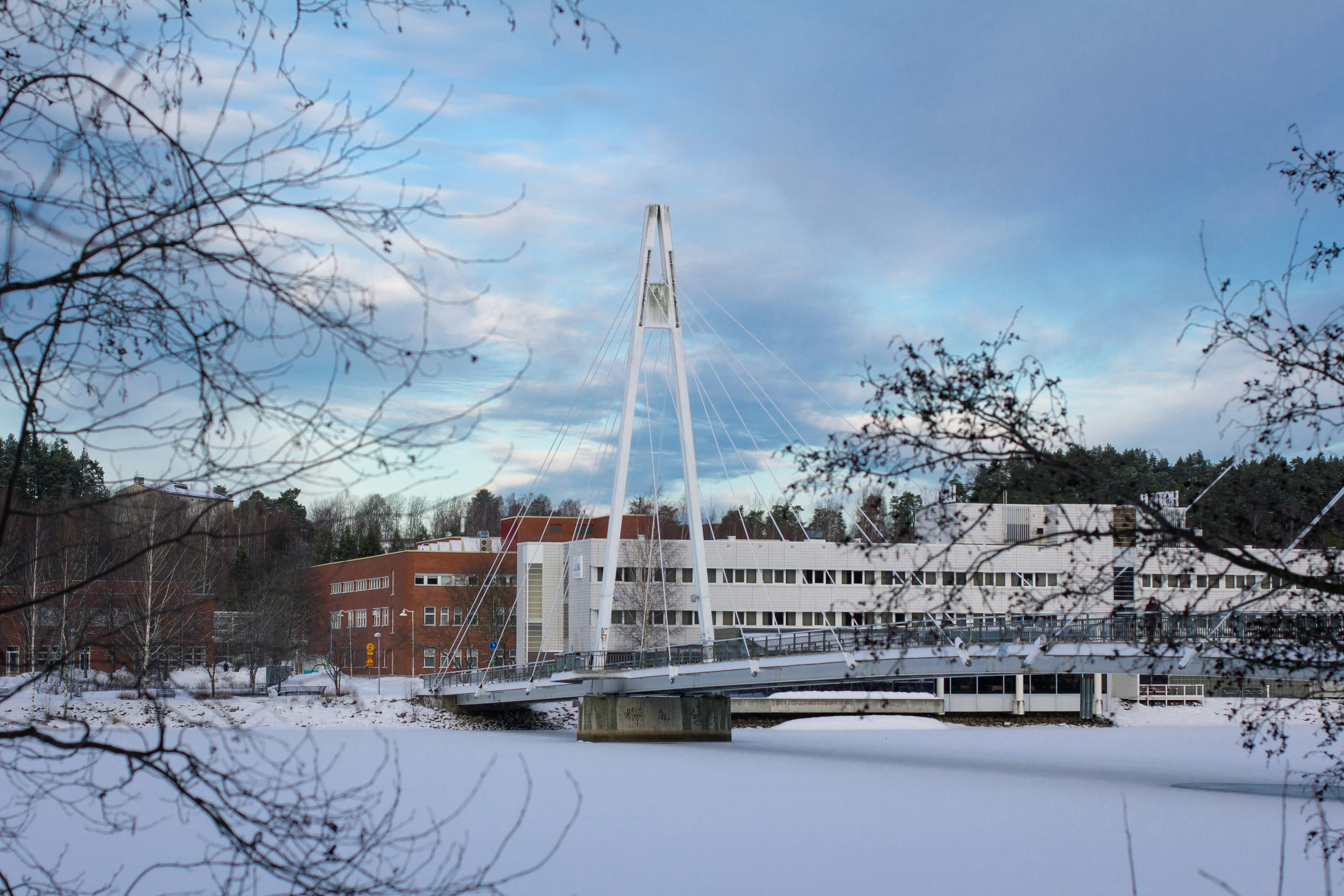 Snow-covered Ylistö Bridge spans a frozen landscape under a clear blue sky.