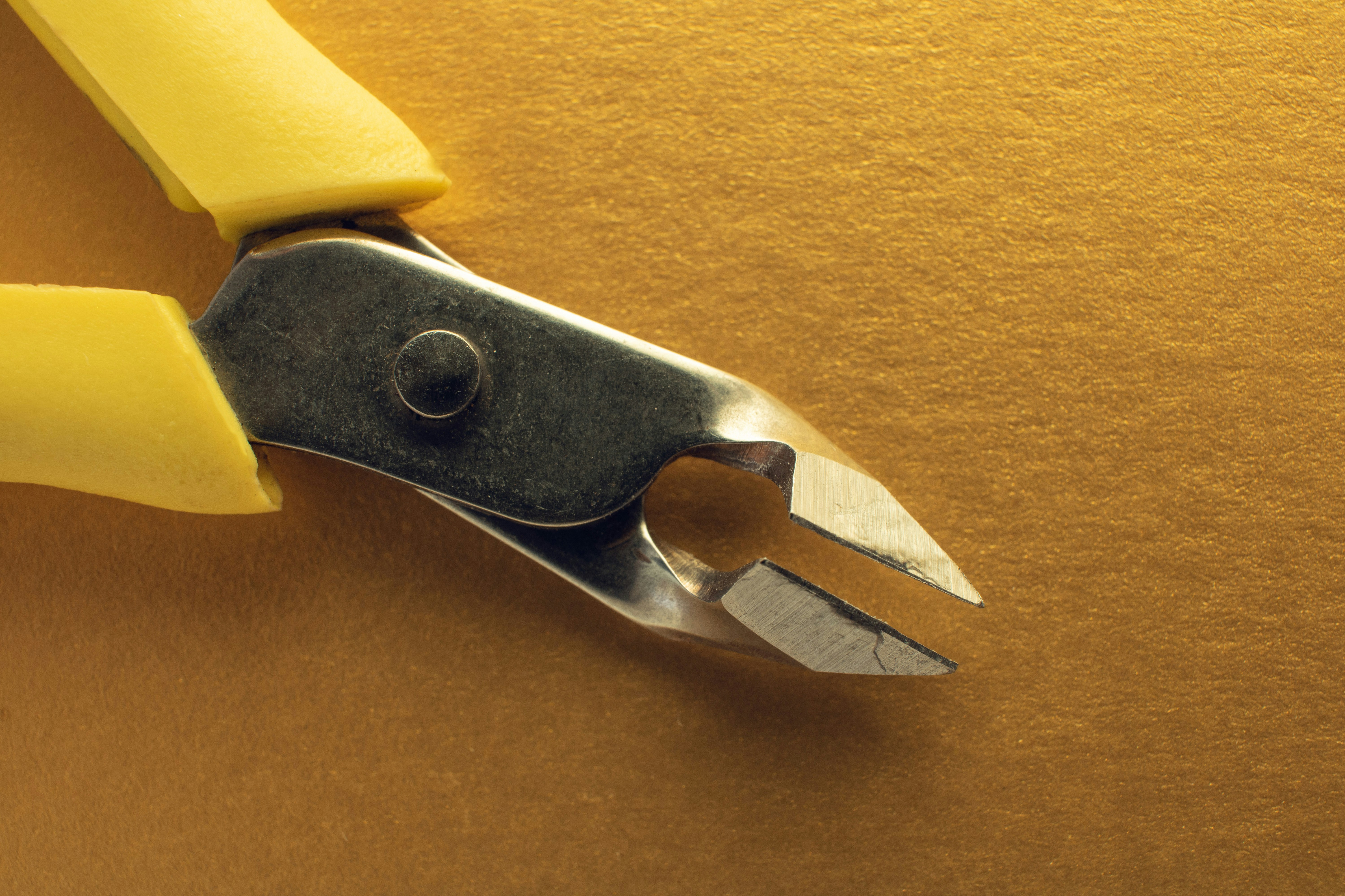 A pair of pliers cutting a piece of yellow paper photo – Free Blade ...