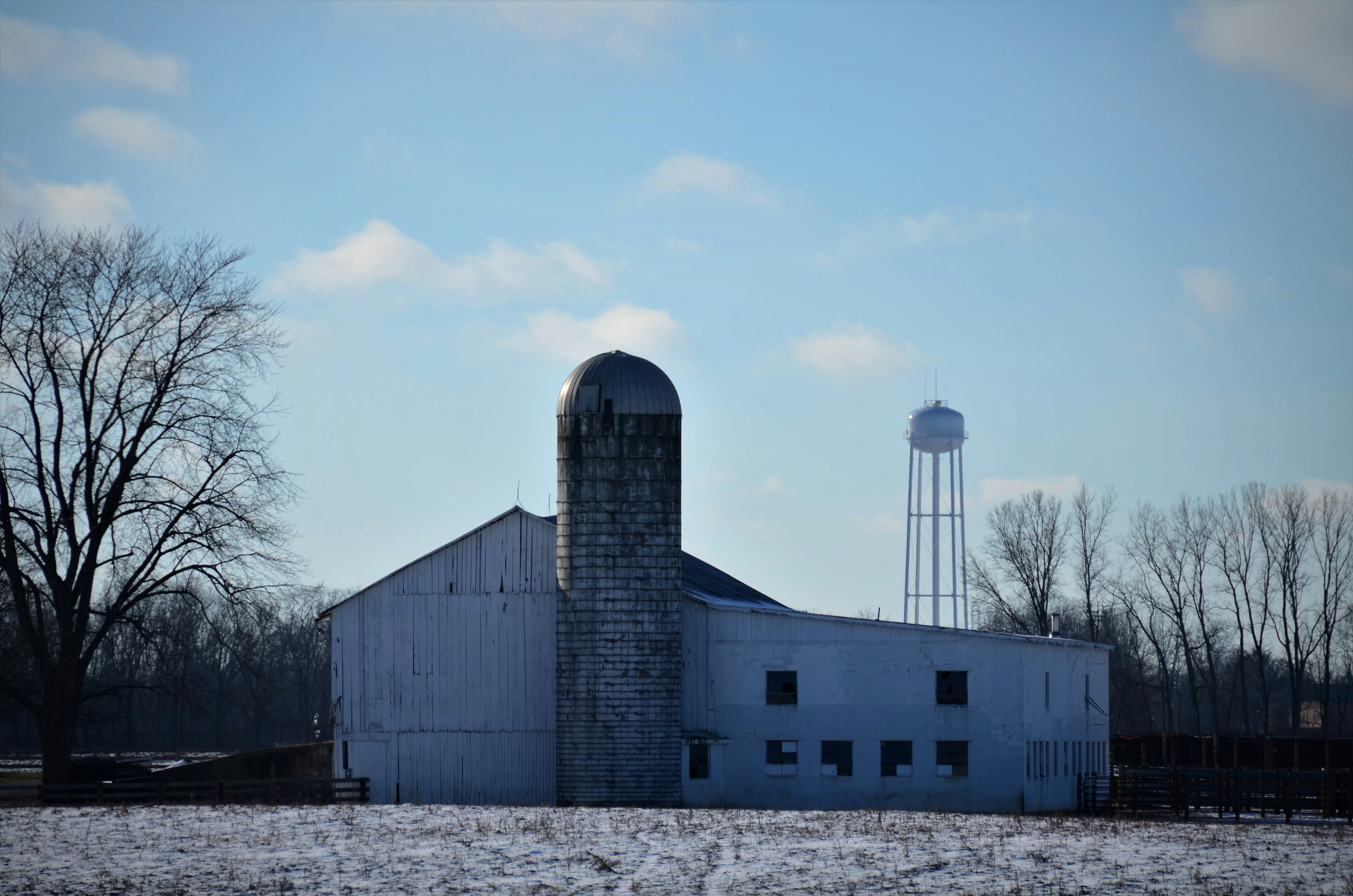A large white barn with a water tower in the background photo – Free ...