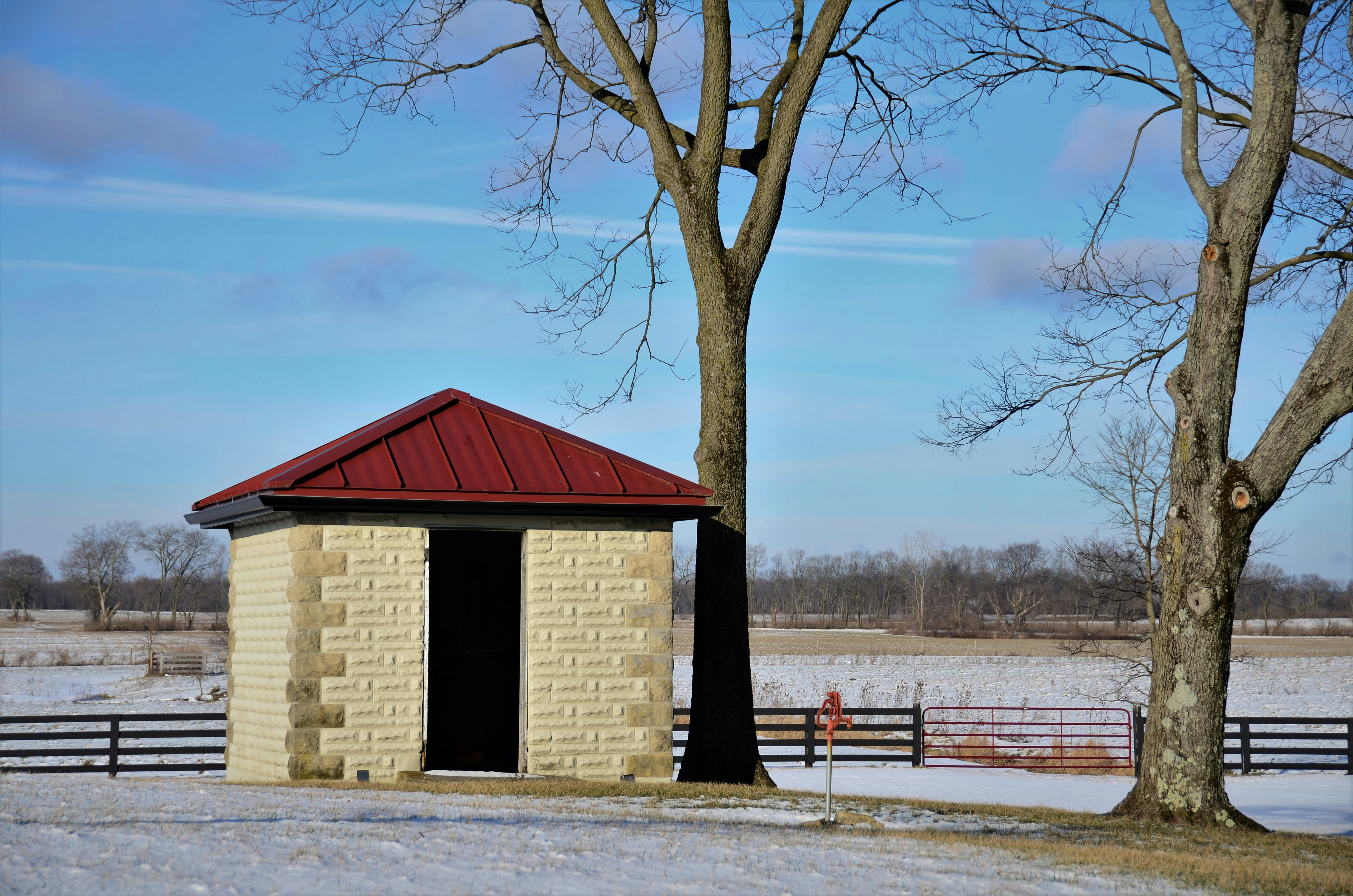 Red-roofed brick shelter by a snow-kissed field