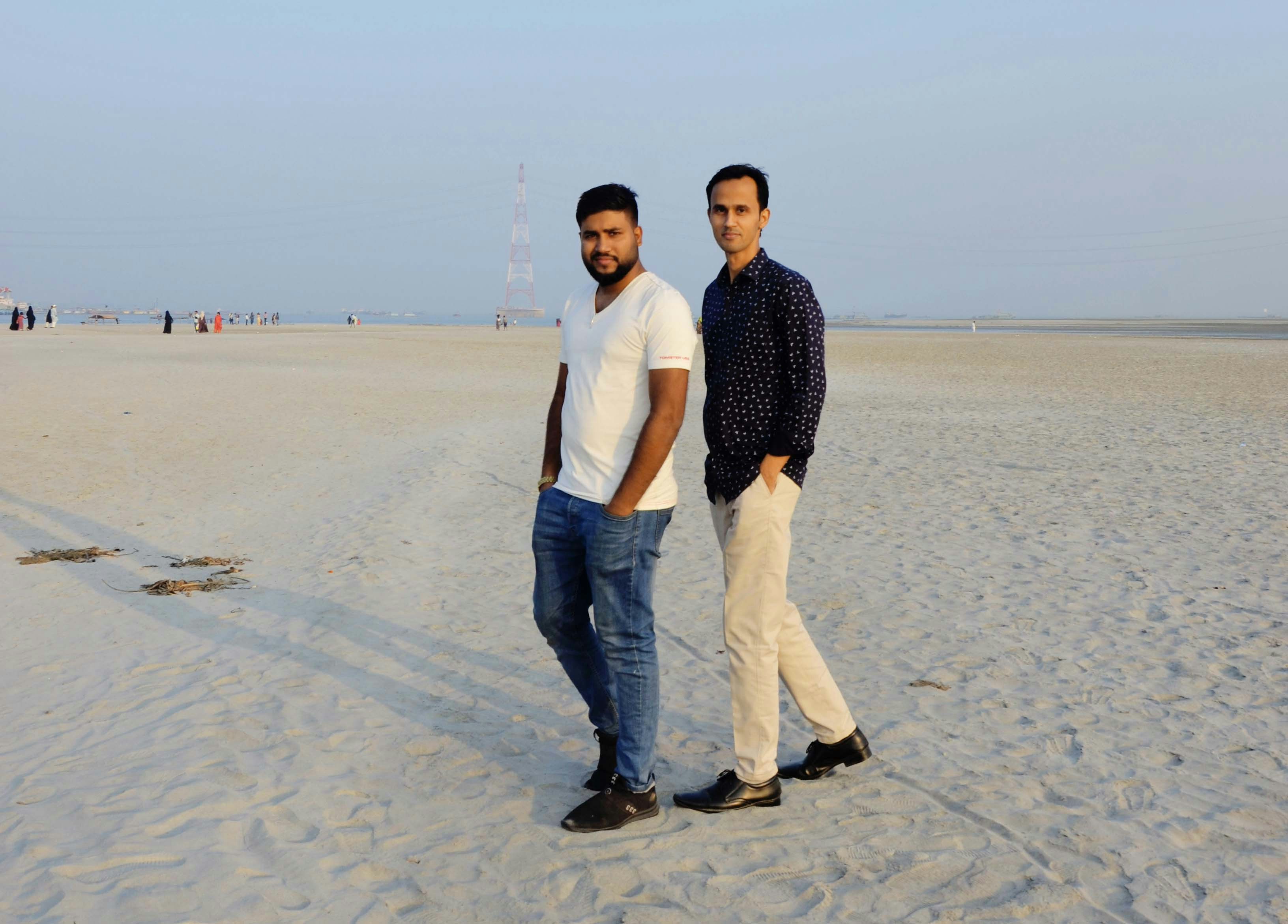 Two men standing on a beach next to each other photo – Free Beach Image ...