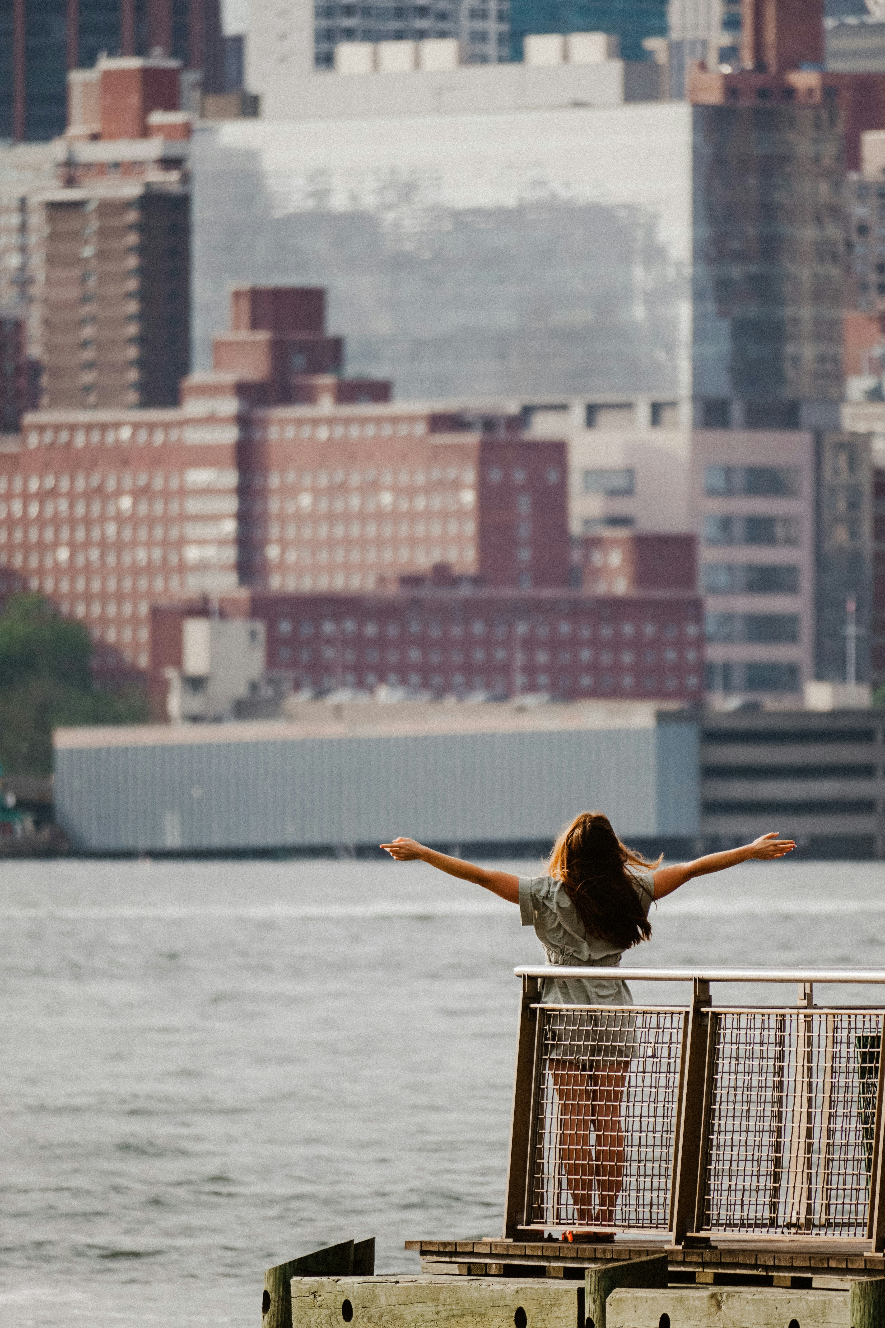 Arms Wide Over the River: A Moment of Freedom Beneath the City