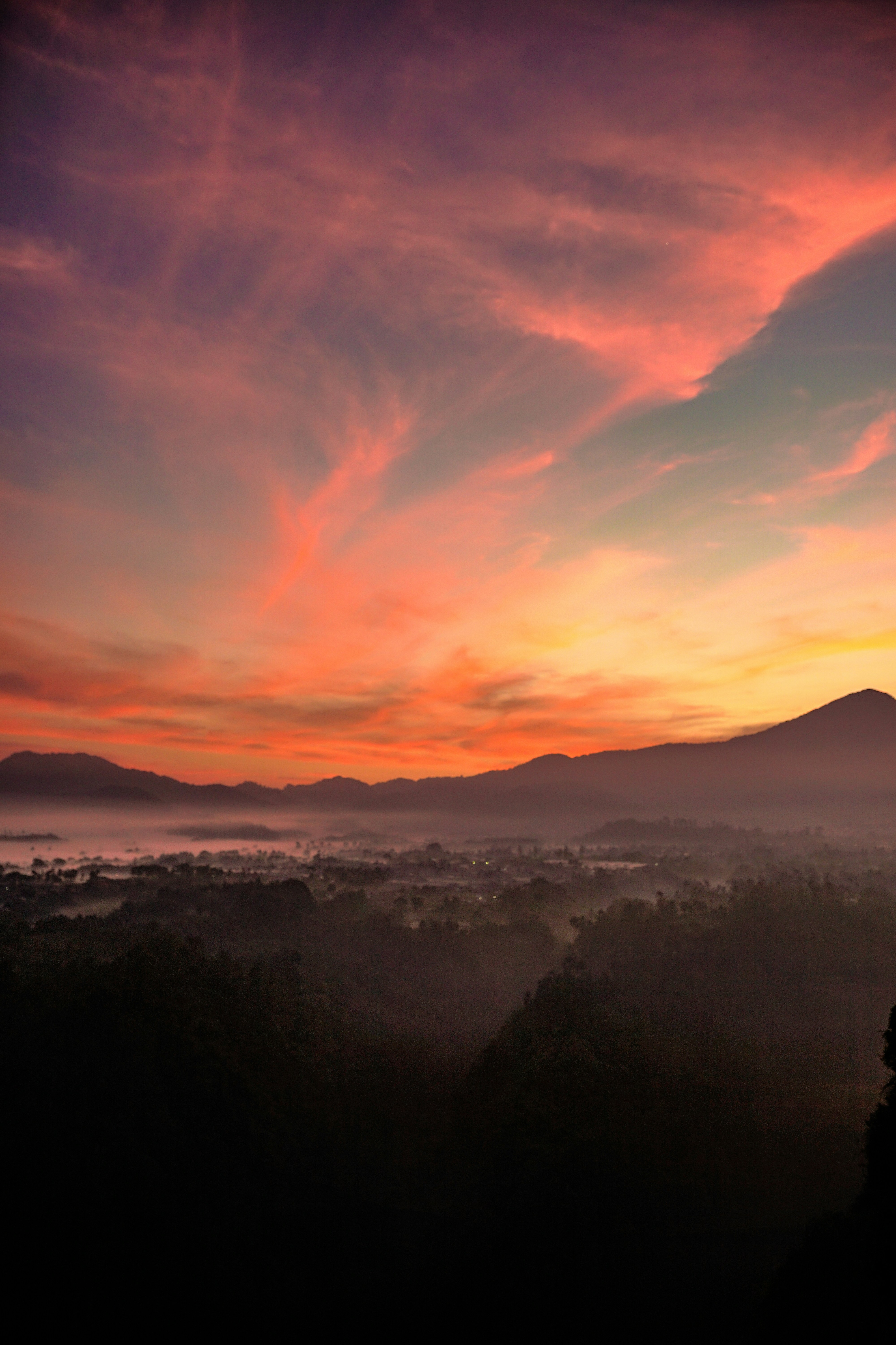 A view of a sunset over a valley with a mountain in the distance photo ...