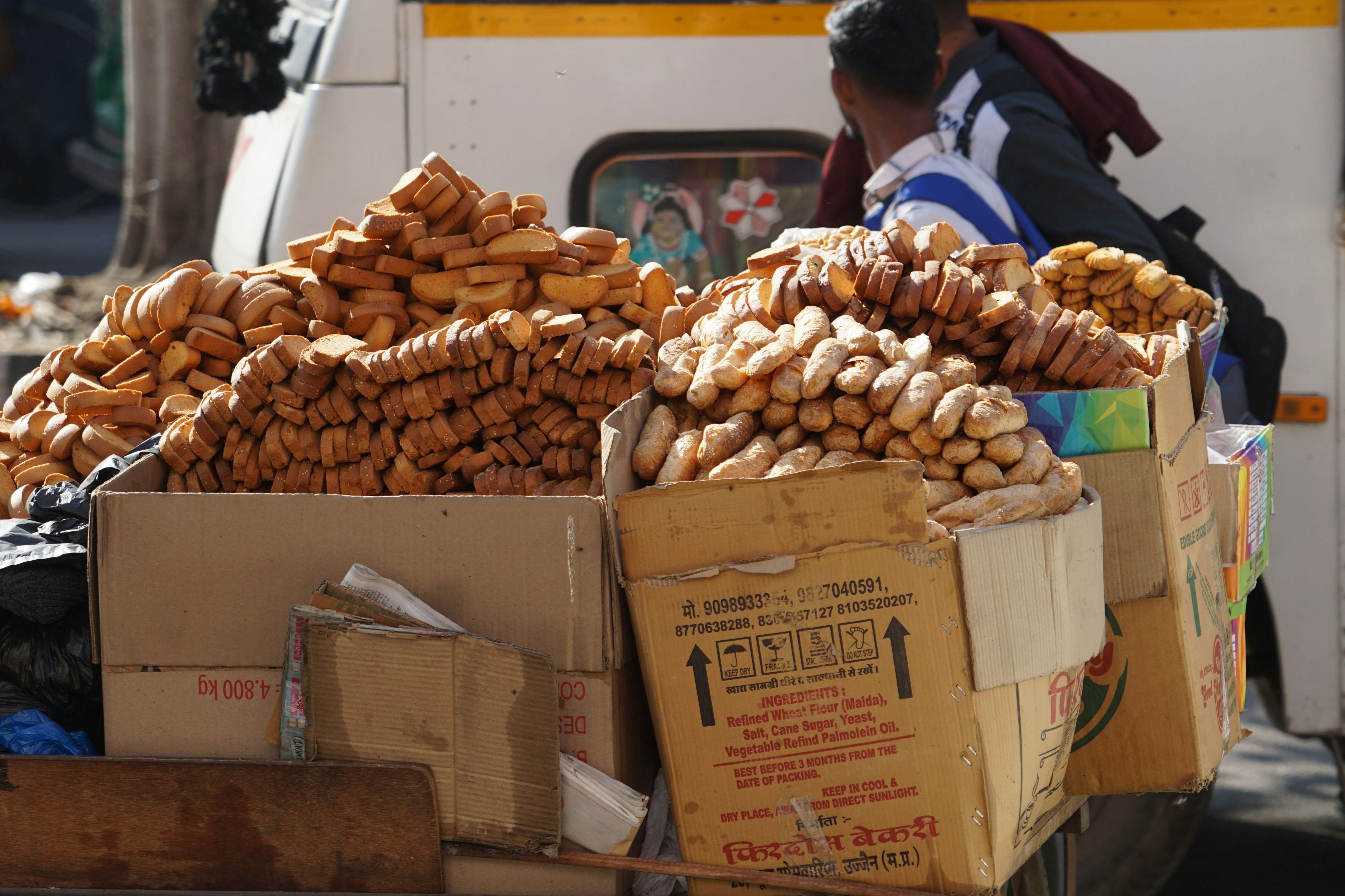 Sunlit Baguettes Piled in Cardboard Crates at a Busy Street Market