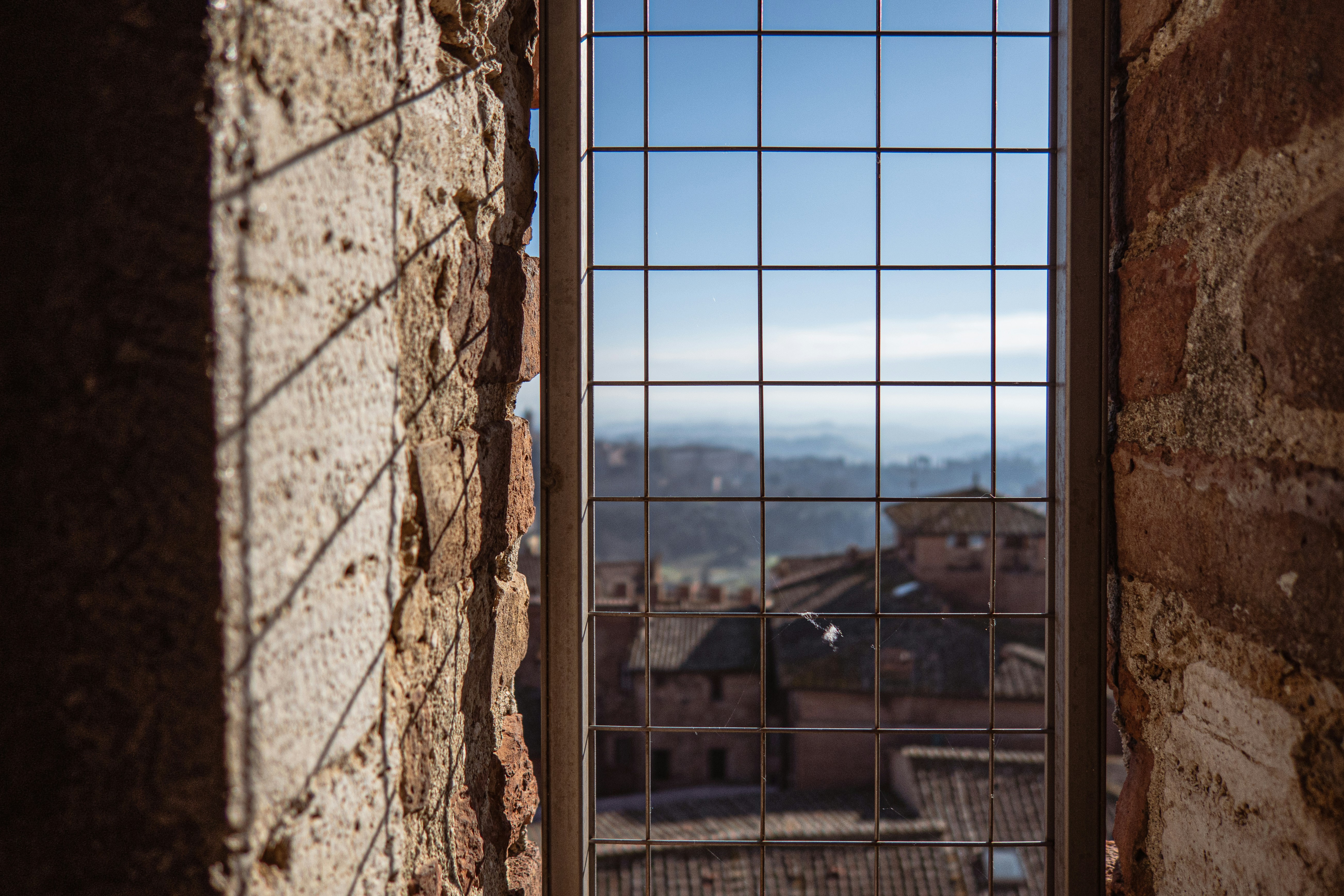 Horizon Framed: Rooftops and Distant Peaks through a Stone Window Grid
