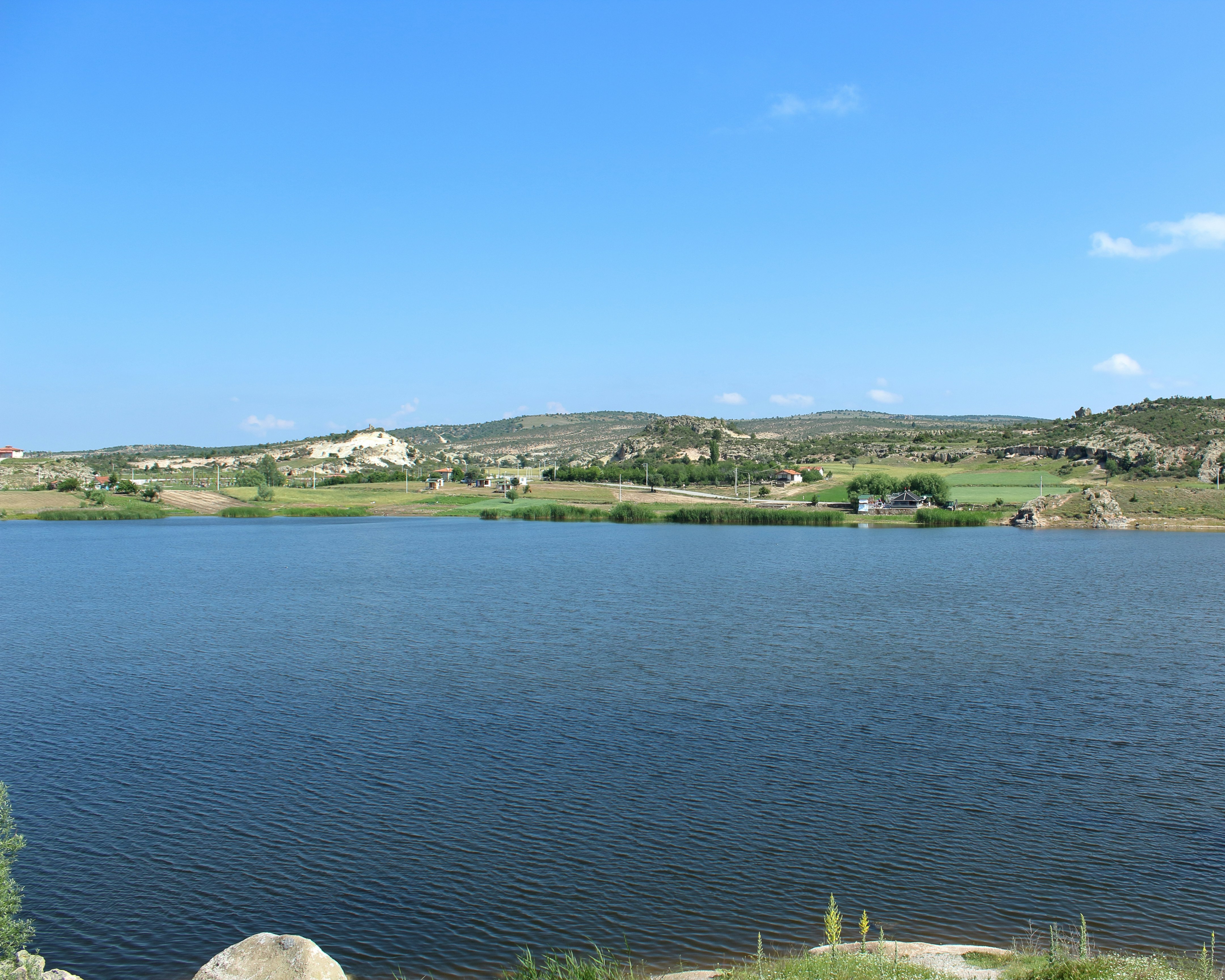 a large body of water surrounded by a lush green hillside