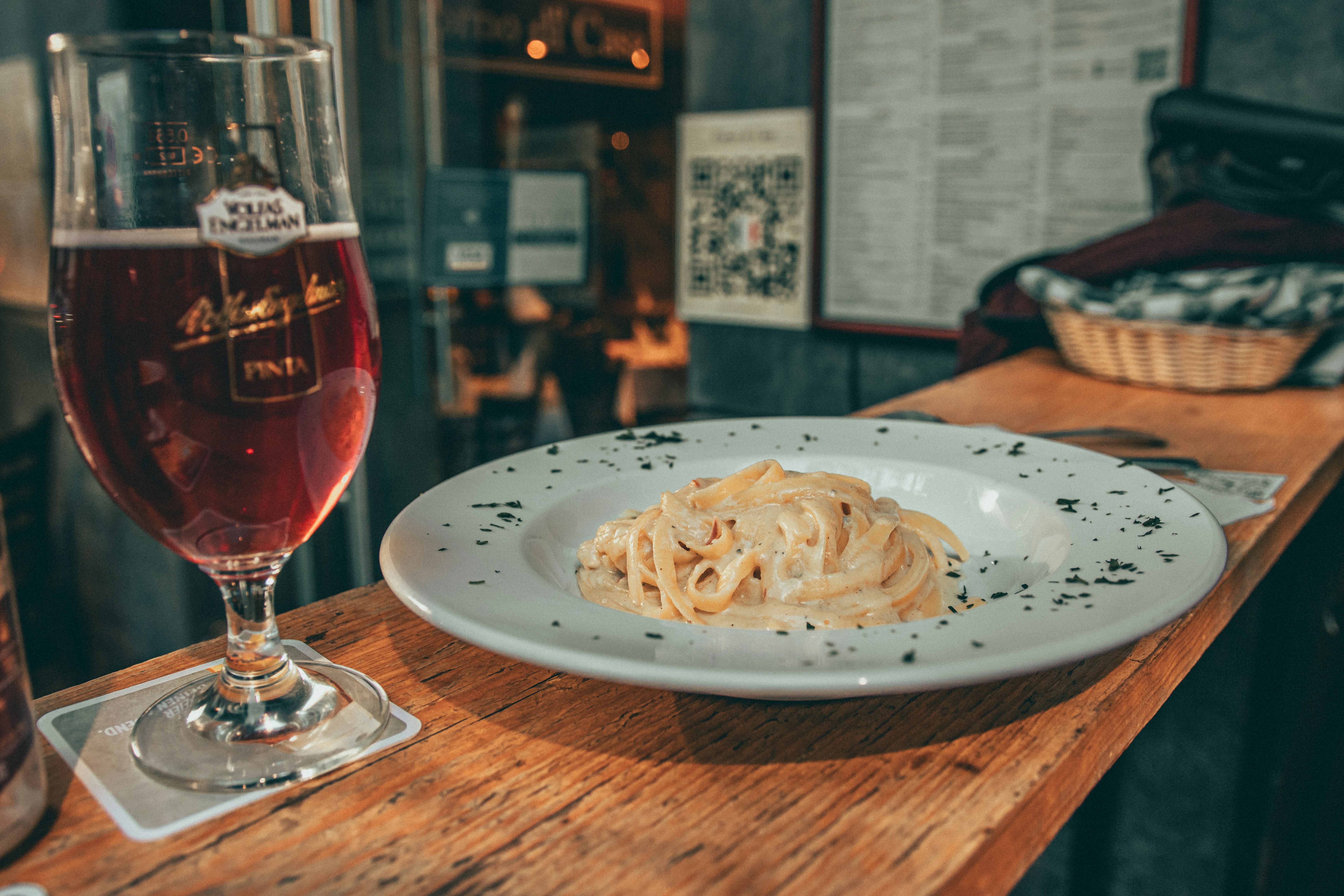 Amber Ale Beside Creamy Pasta on a Warm Bar Counter
