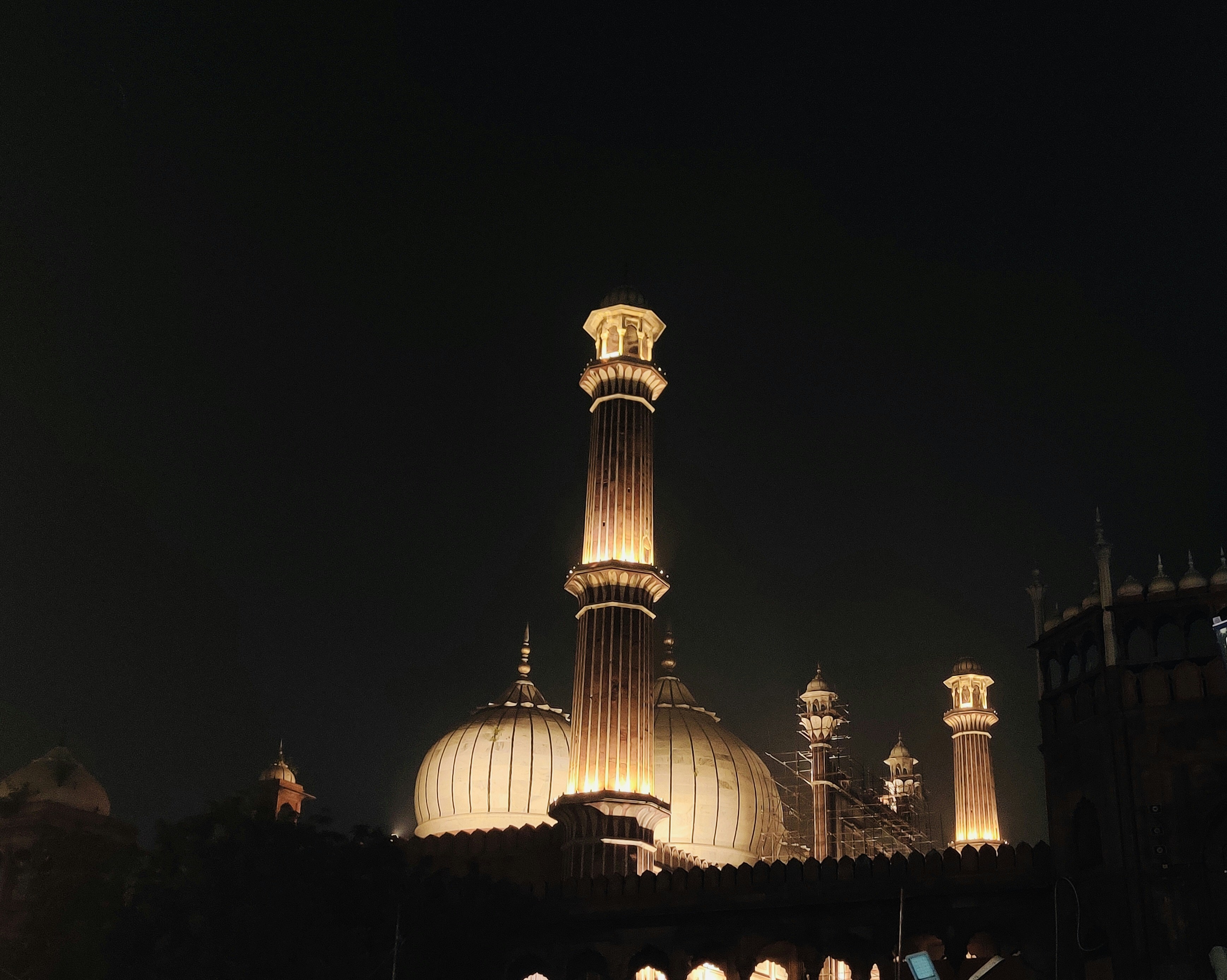 Illuminated domes and minarets of a grand mosque against the night sky.