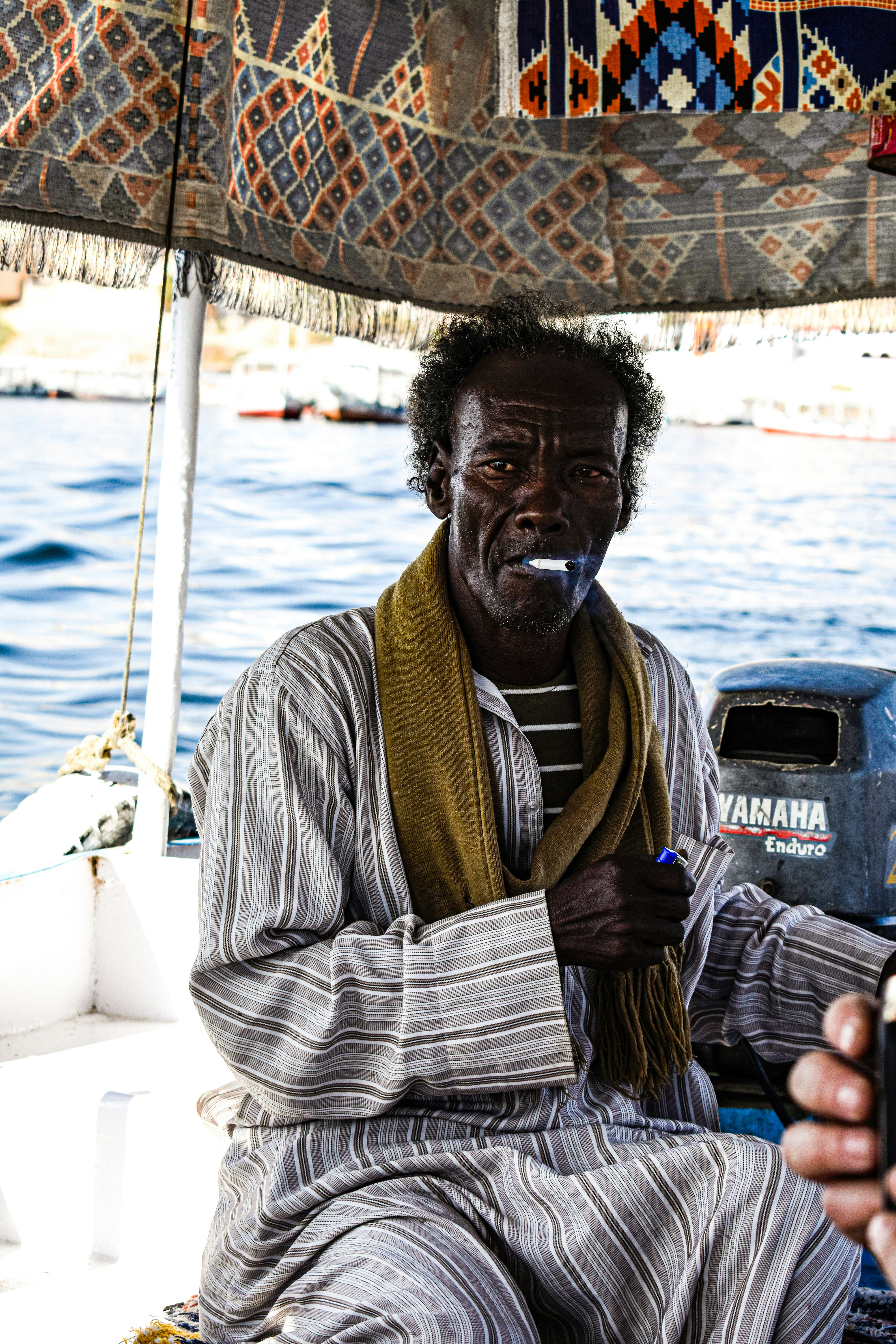 Smoke, Salt, and Sun: A Fisherman Under a Patterned Canopy