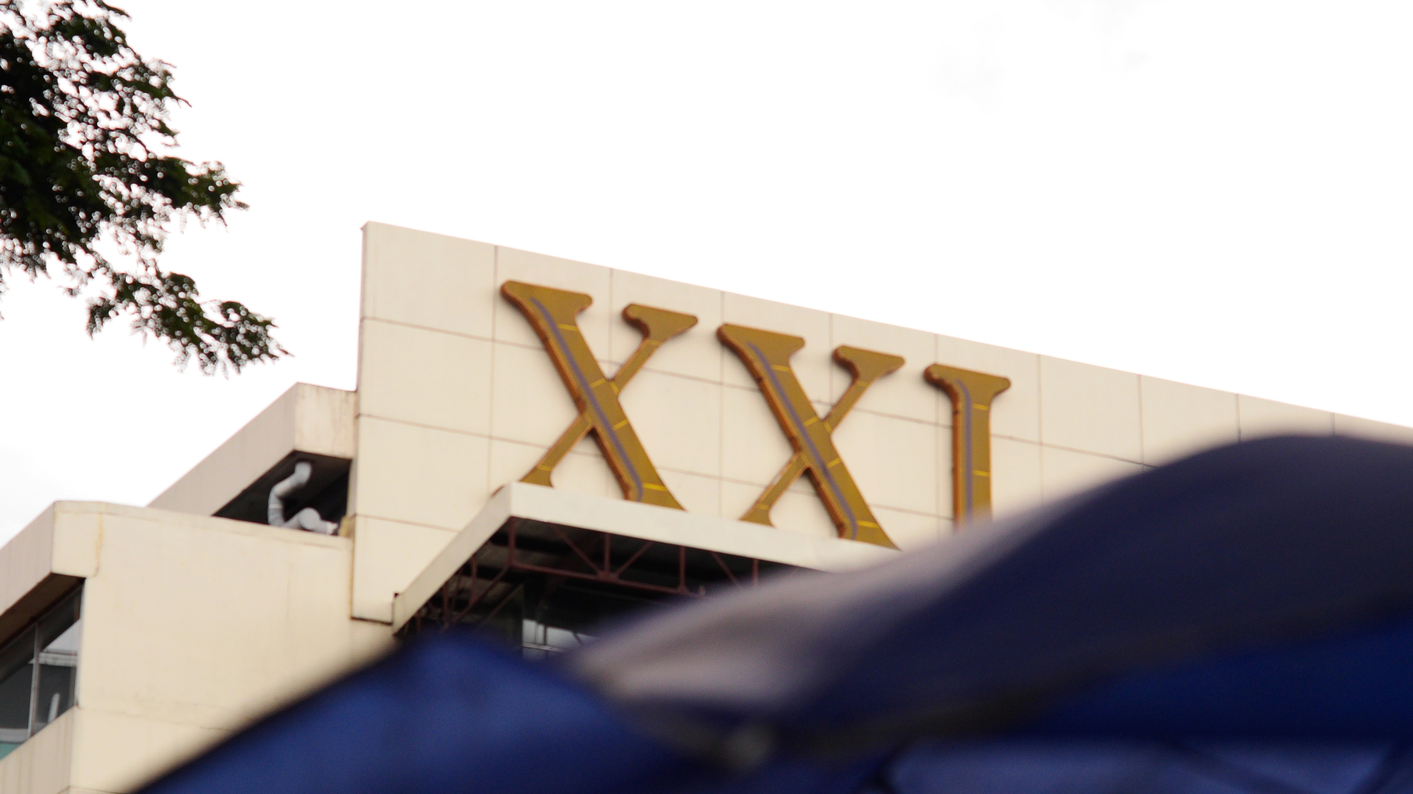 The iconic XX1 sign prominently displayed on a modern building, framed by a blue canopy in the foreground. 