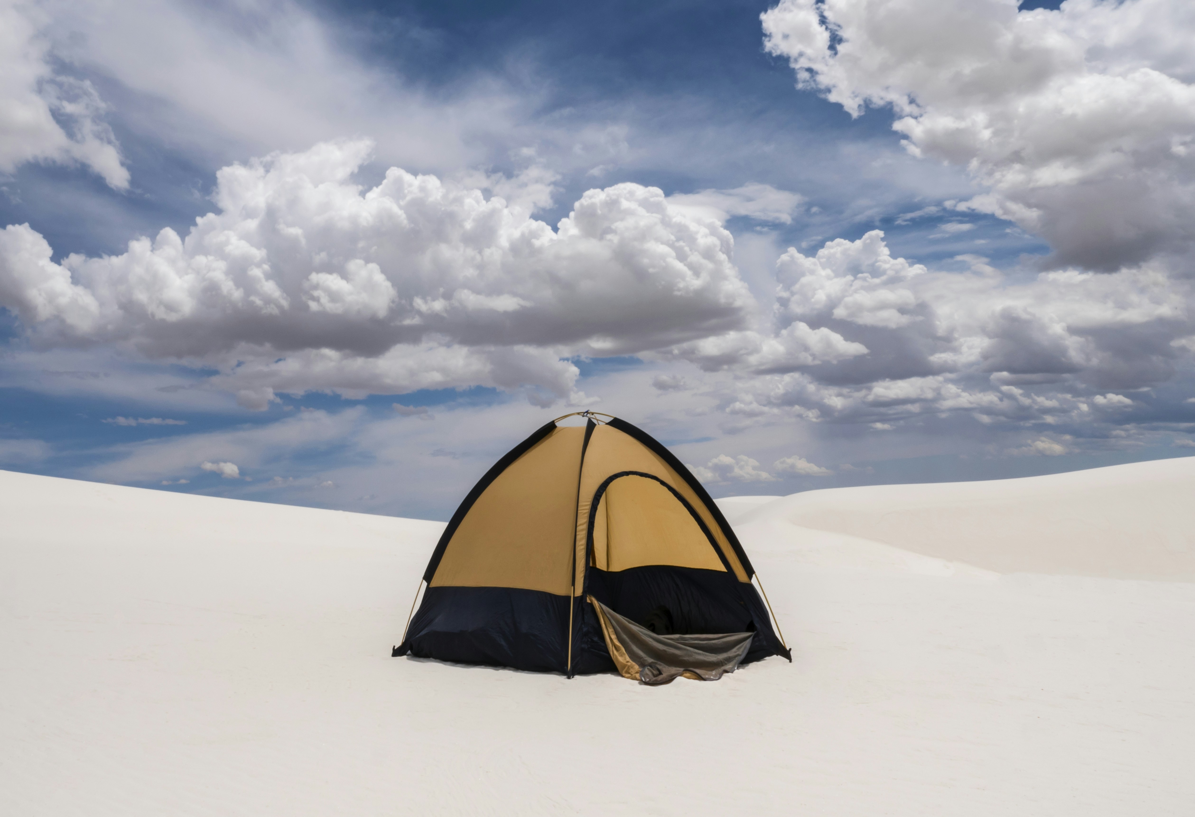 a tent in the middle of a desert under a cloudy sky