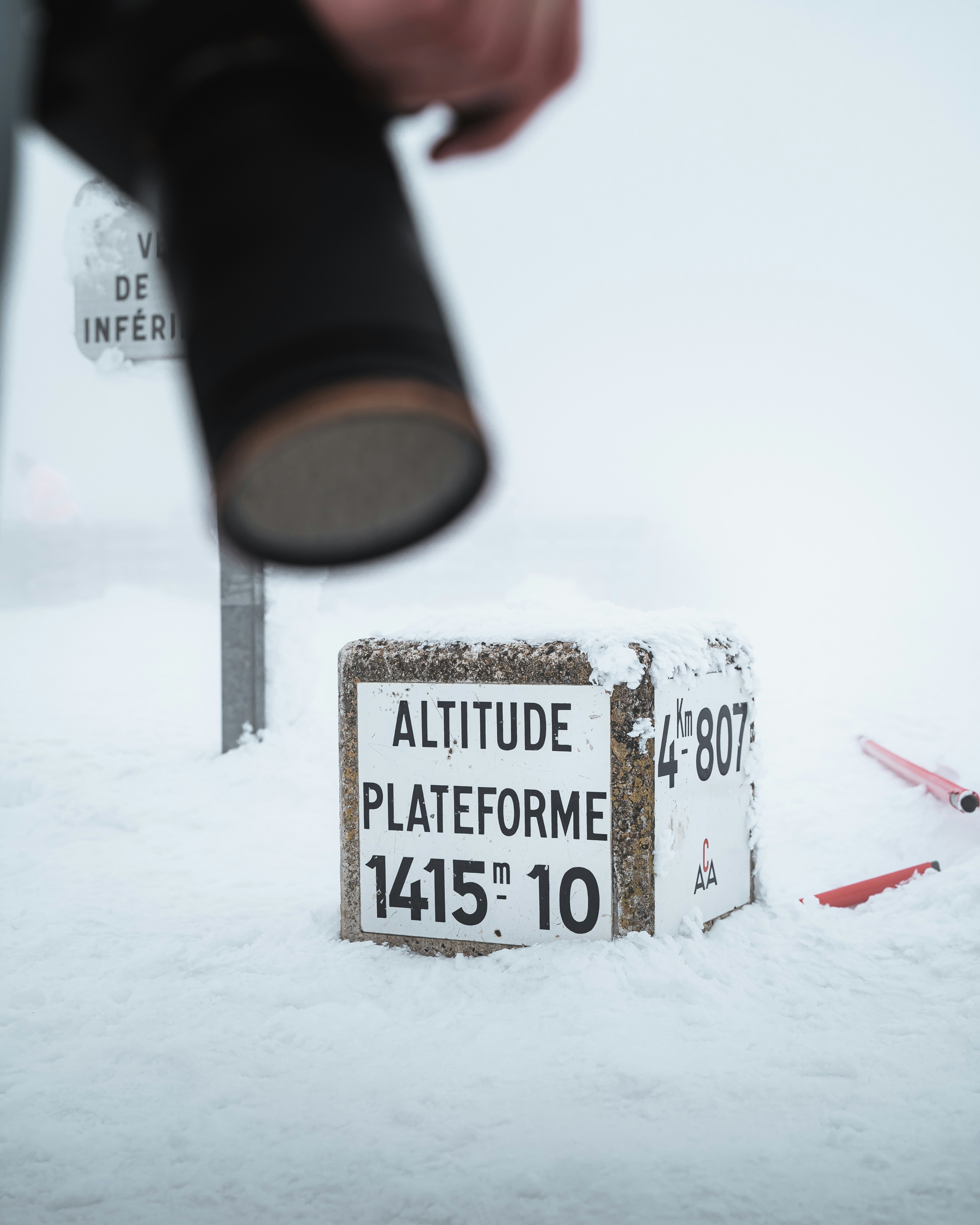 A Frost-Laced Altitude Marker Framed by a Blurred Foreground Lens
