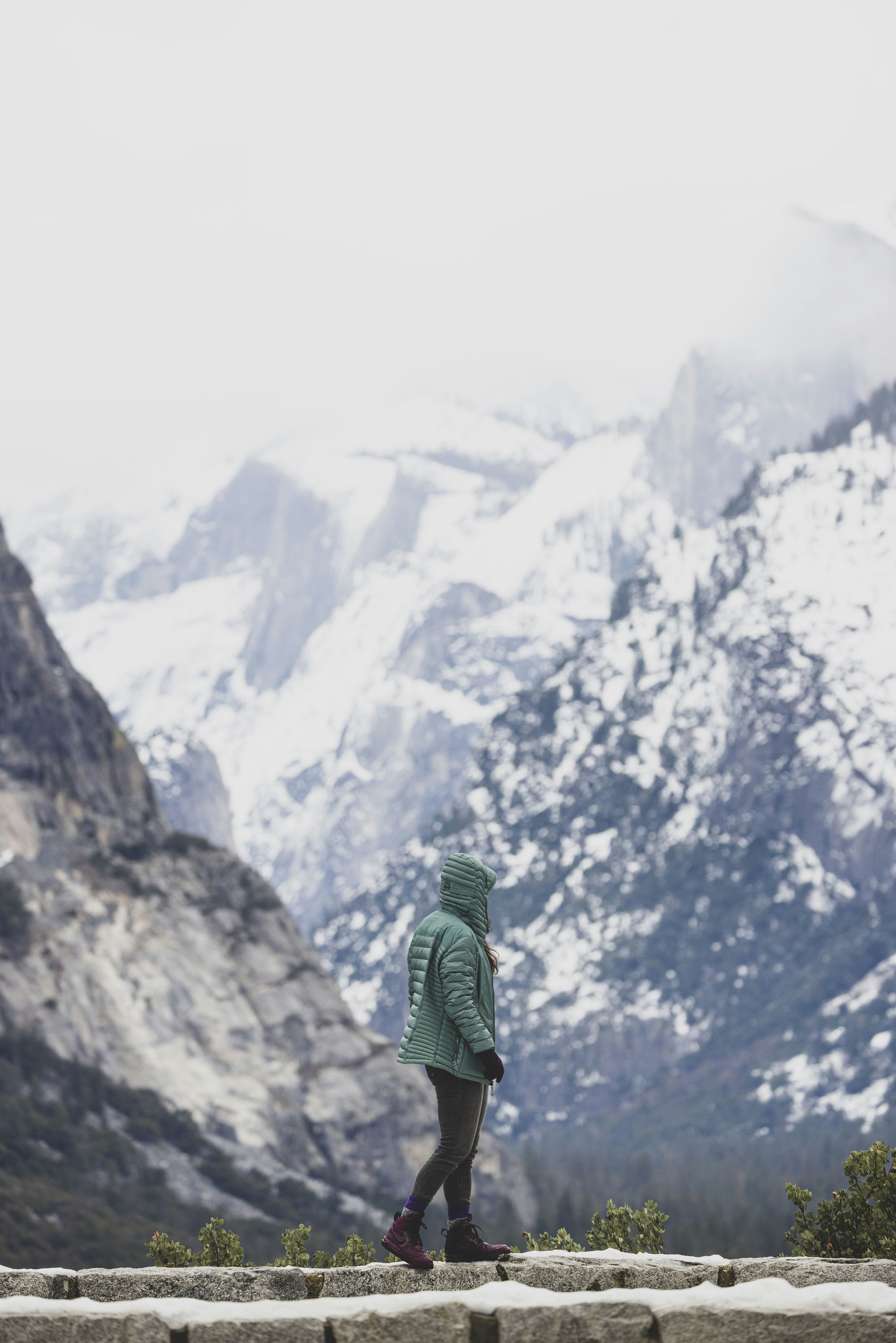A person standing on a ledge looking at mountains photo – Free Woman ...