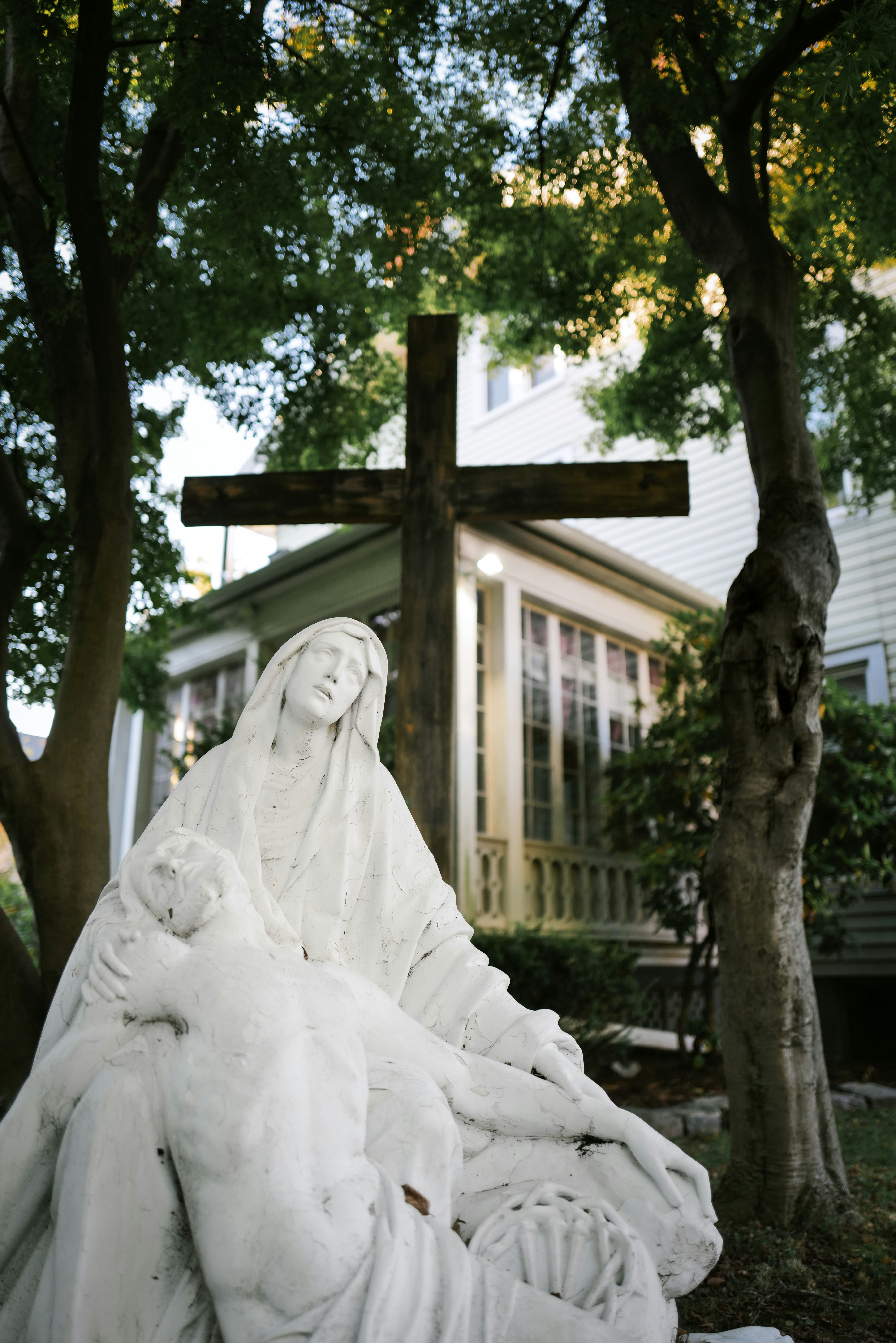 a statue of a woman sitting in front of a cross