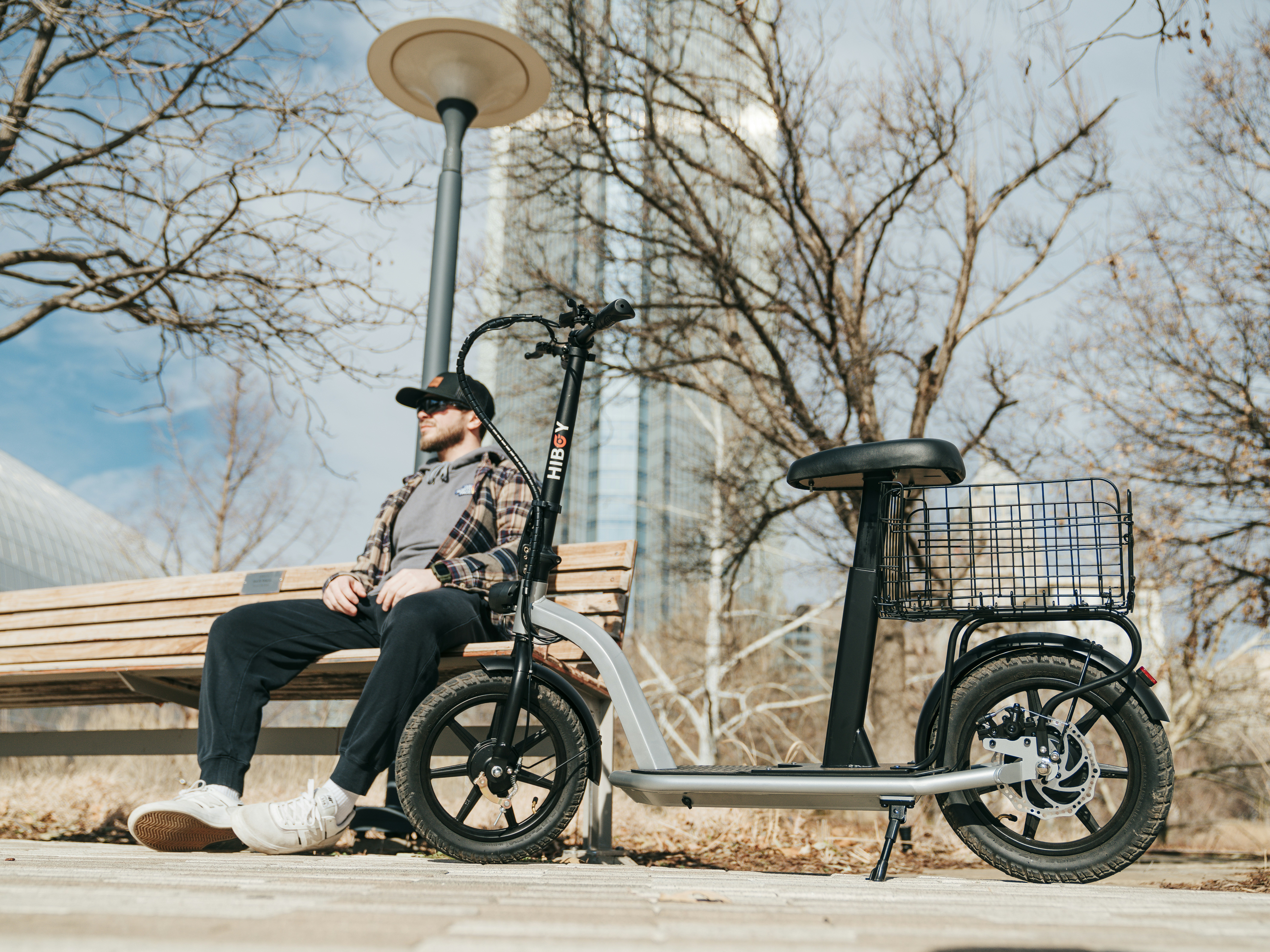 A man sitting on a bench next to a scooter photo – Free Electric ...