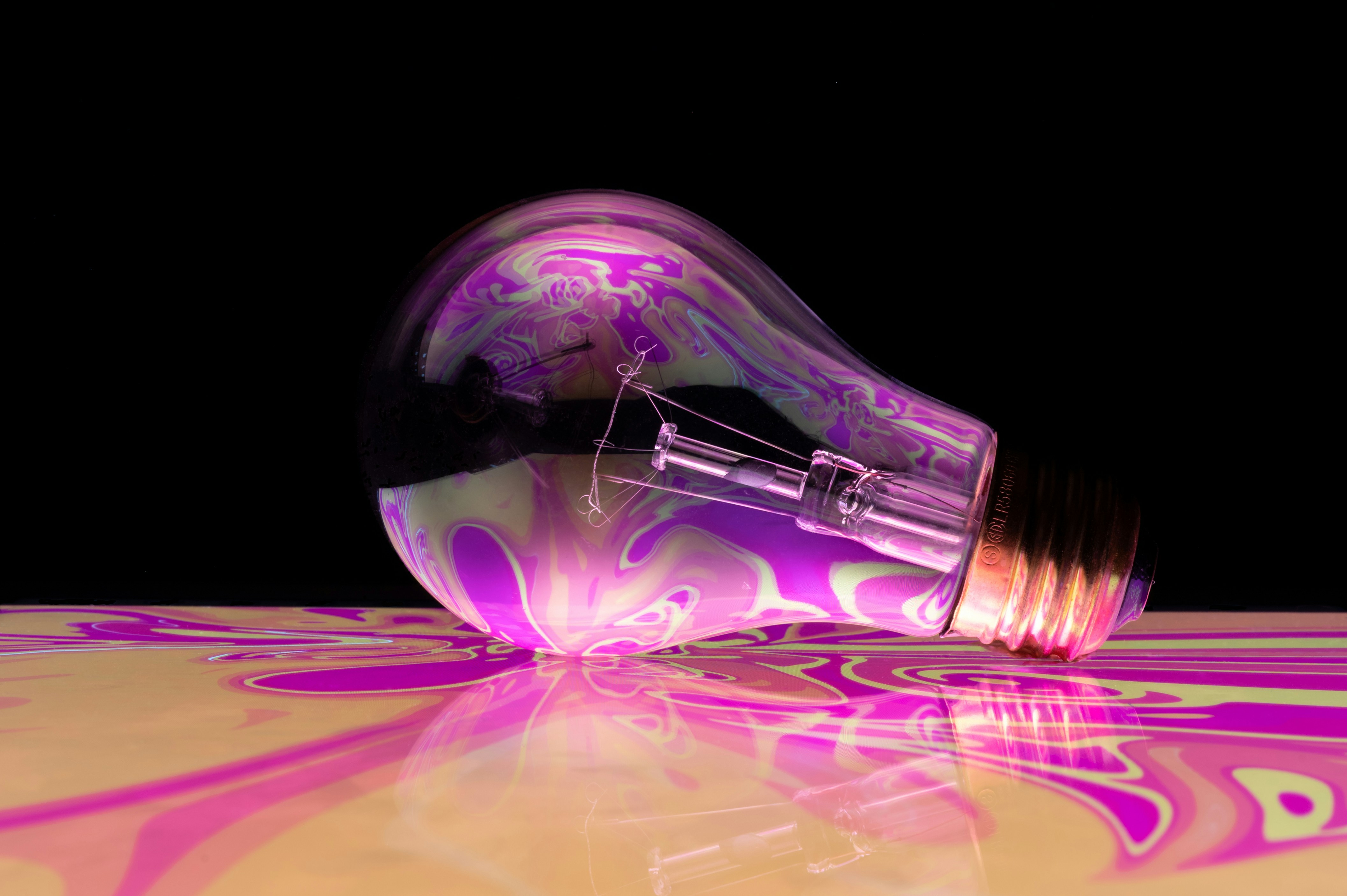 Glass in Bloom: A Lightbulb Resting on Neon-Pink Swirls
