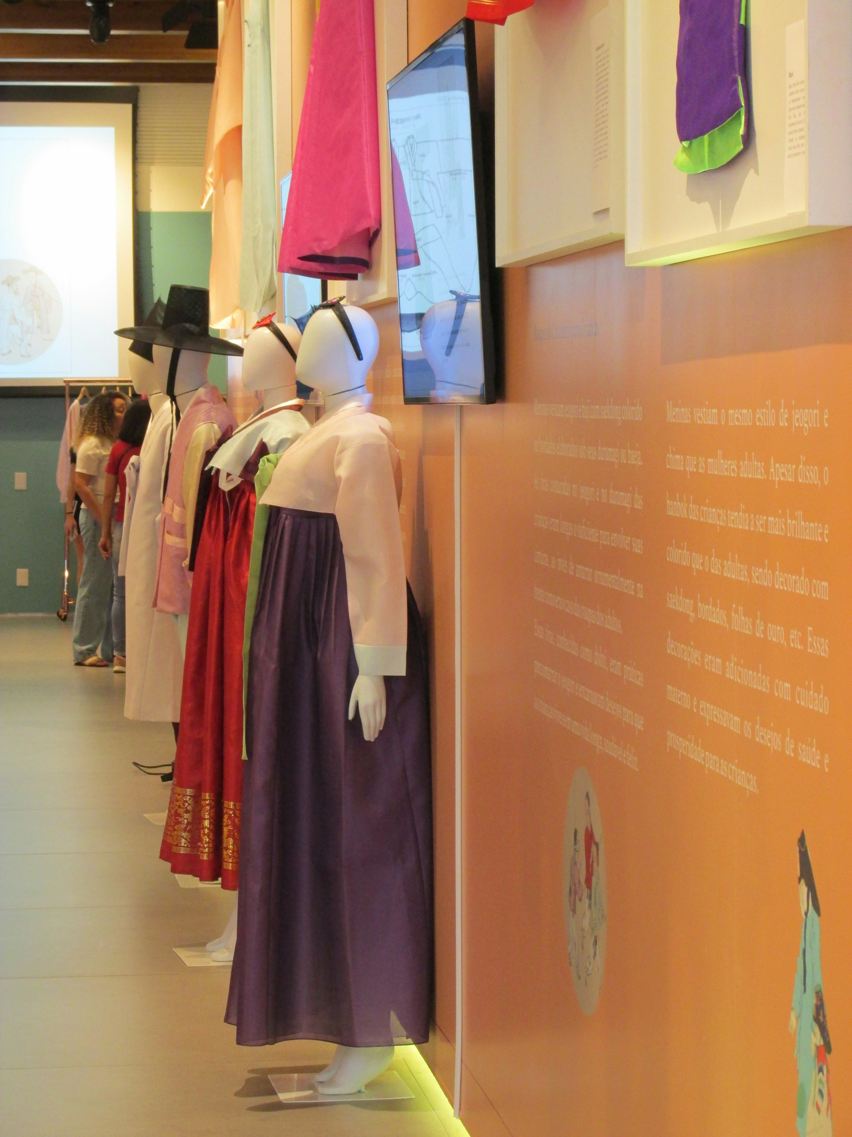 Velvet Parade: A Row of Gowns Beneath an Amber Gallery Wall