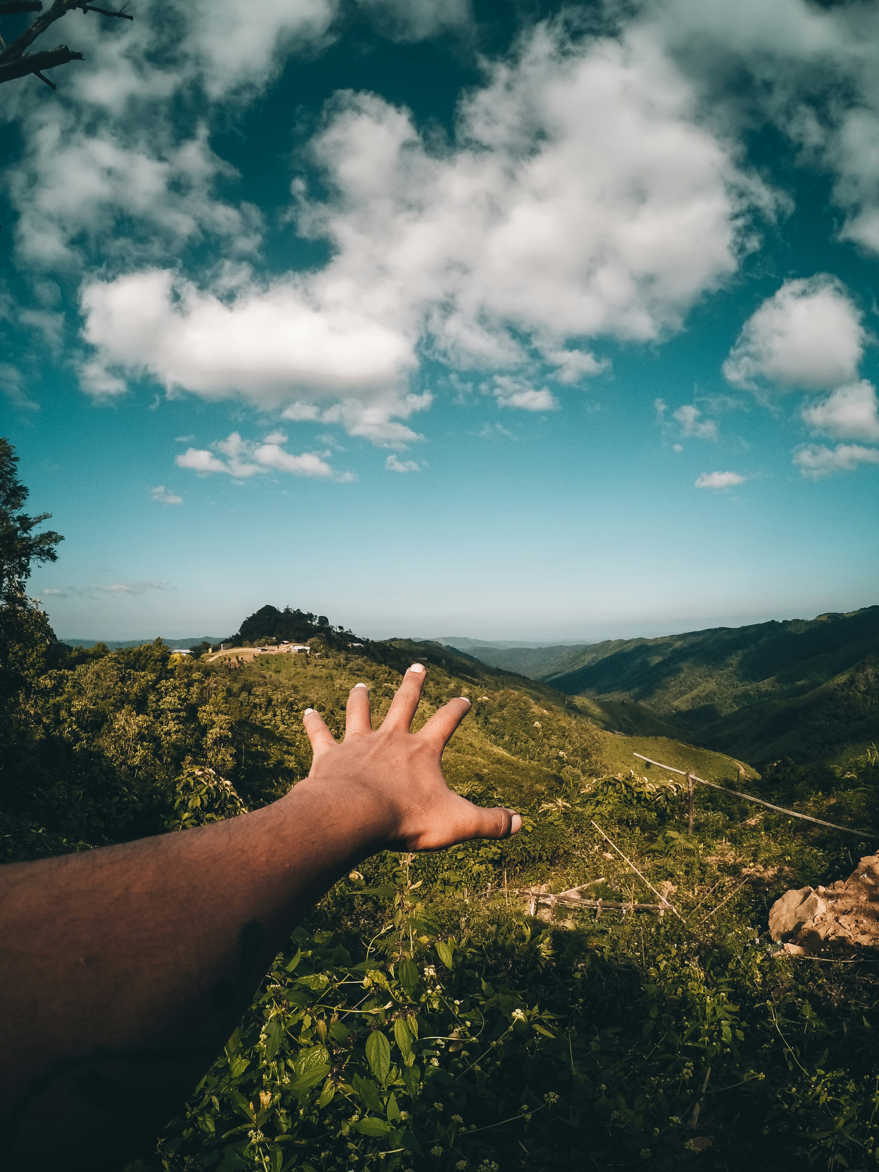 A hand reaching up into the sky with a mountain in the background photo ...