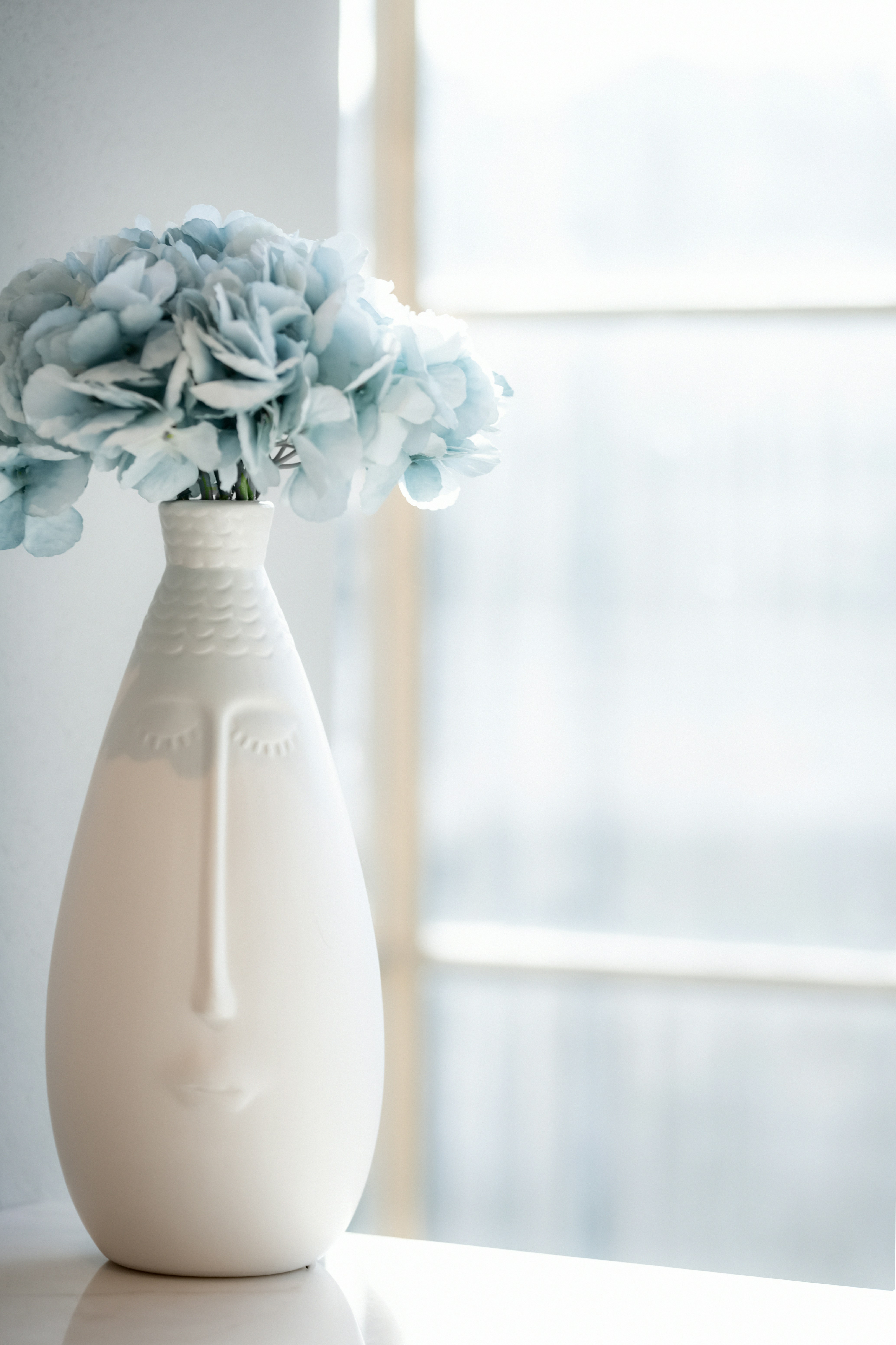 A white vase filled with blue flowers on top of a table photo – Free ...