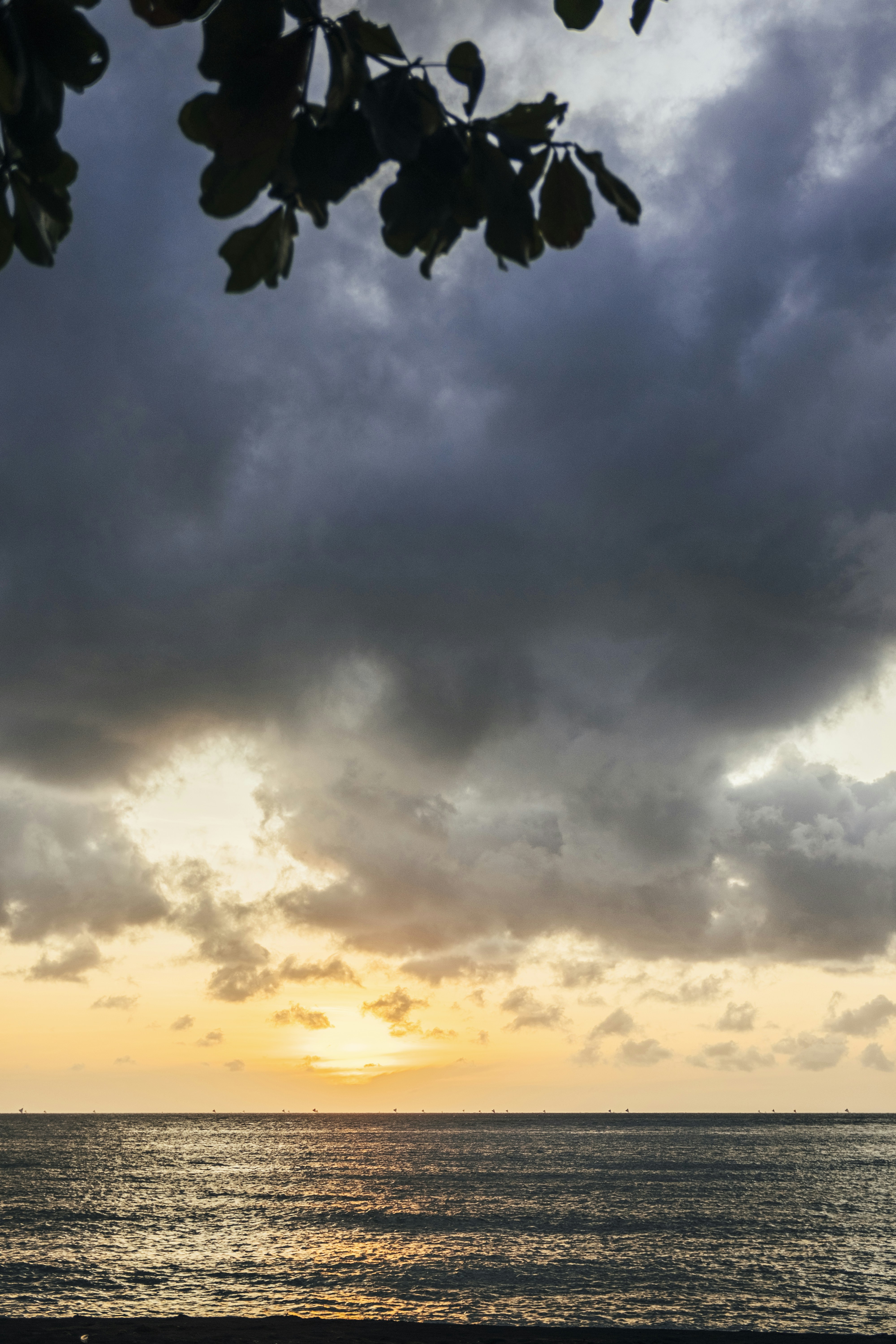 the sun is setting over the ocean on a cloudy day