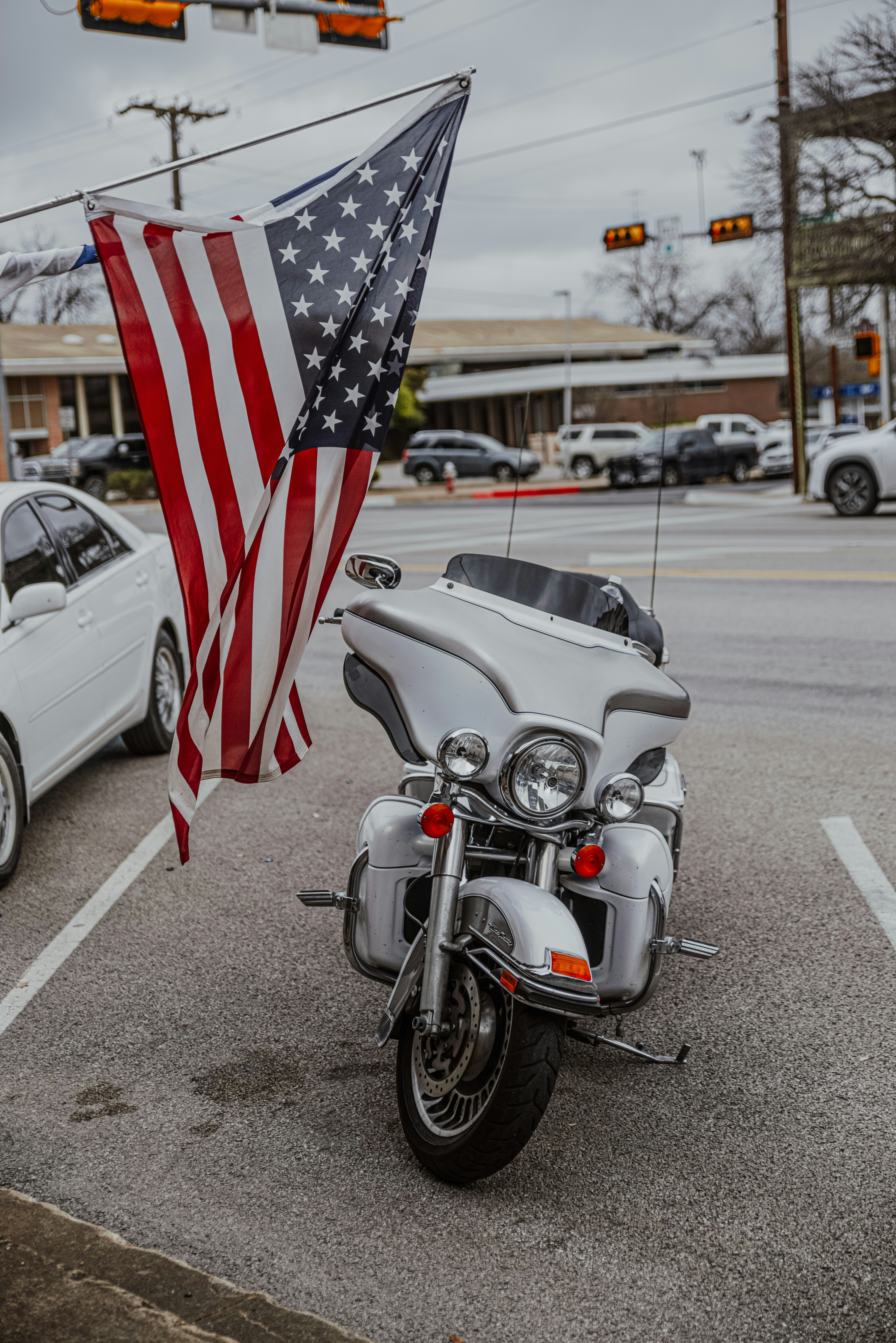 Flag-Finned Ride: A Silver Motorbike Stands Proud in the Street Bright with An American Flag